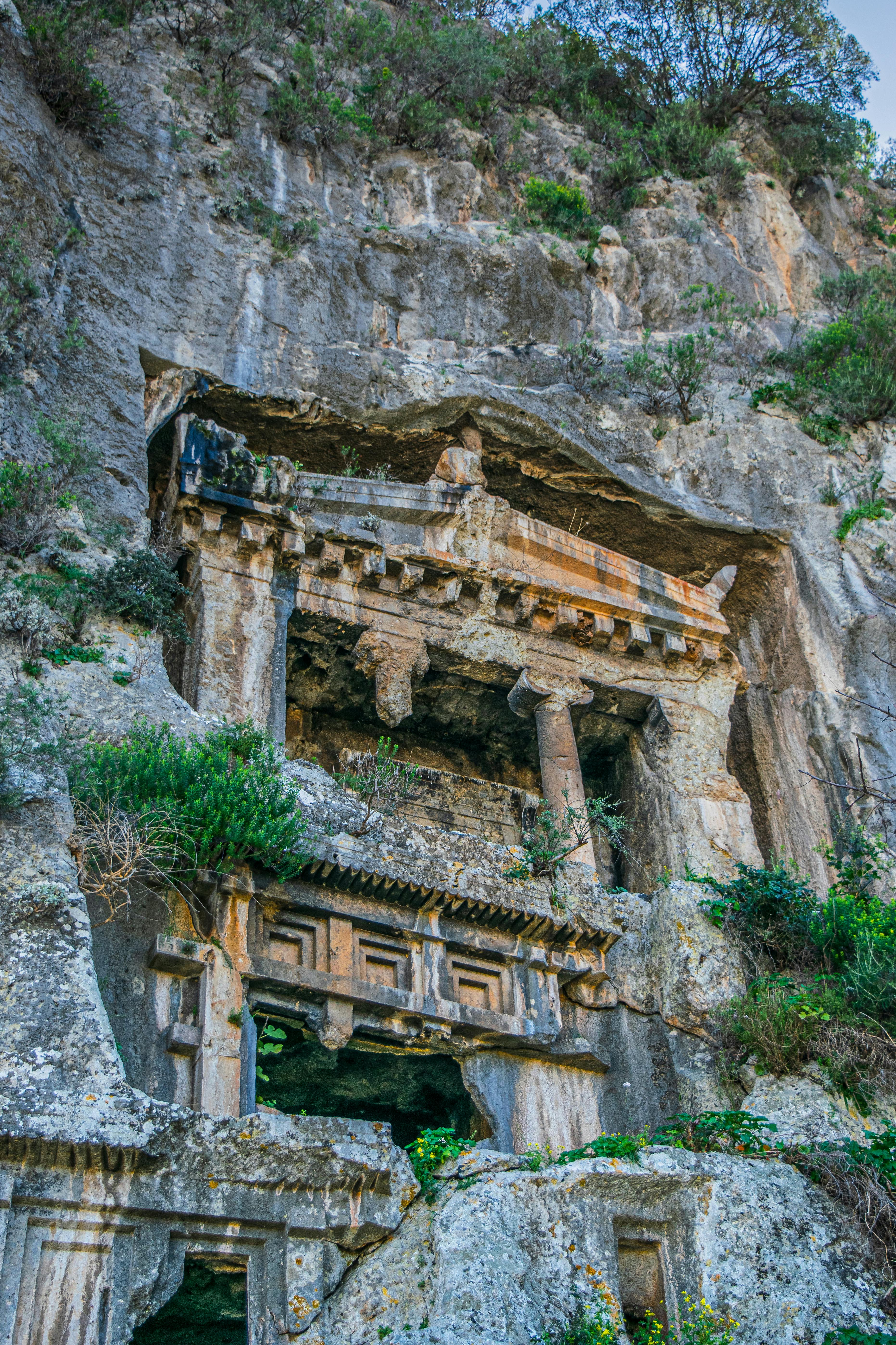 Ancient Rock Tomb with Vegetation in Cliff Face · Free Stock Photo