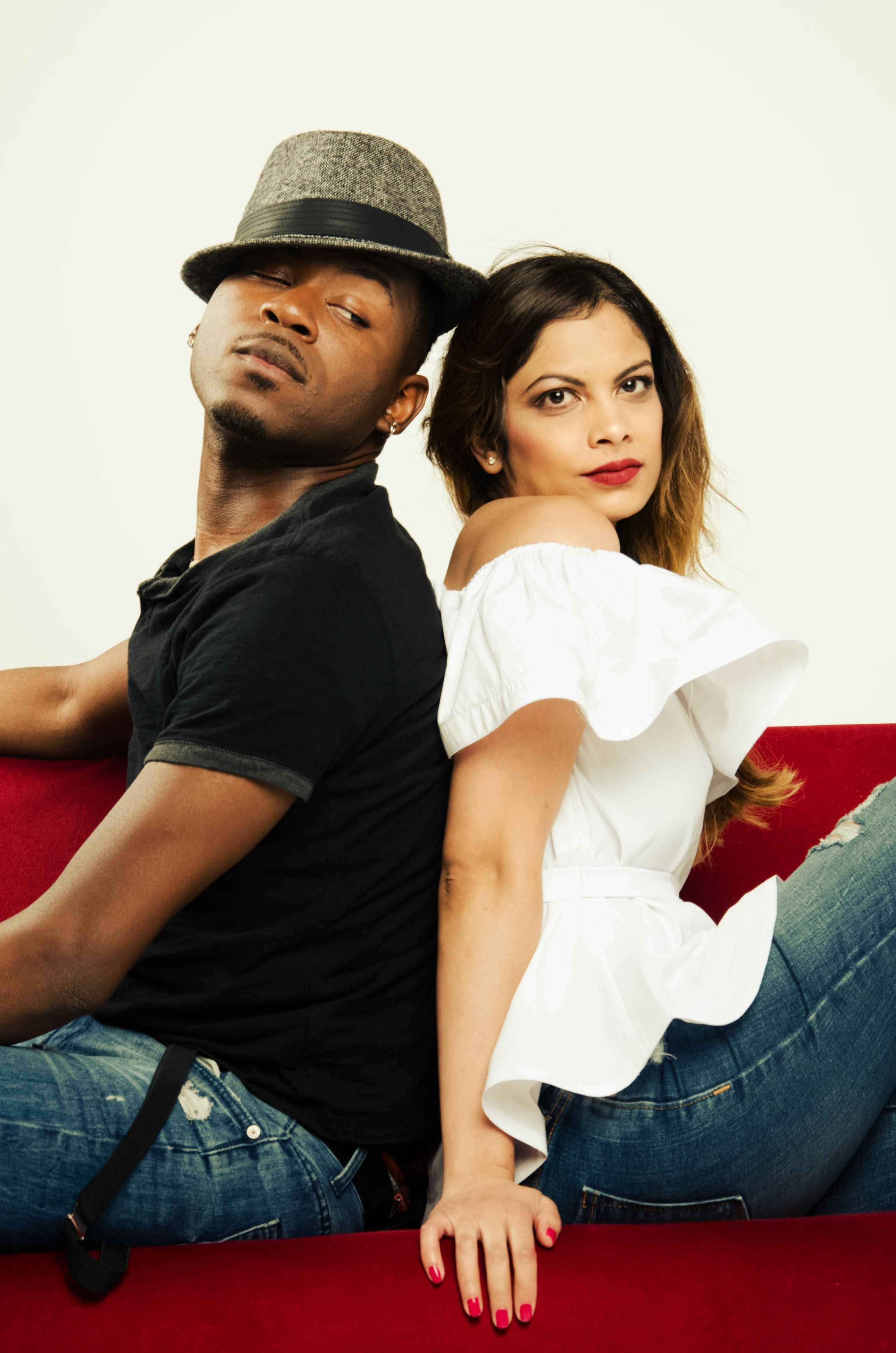 Stylish Couple Posed Back-to-Back on Red Sofa · Free Stock Photo