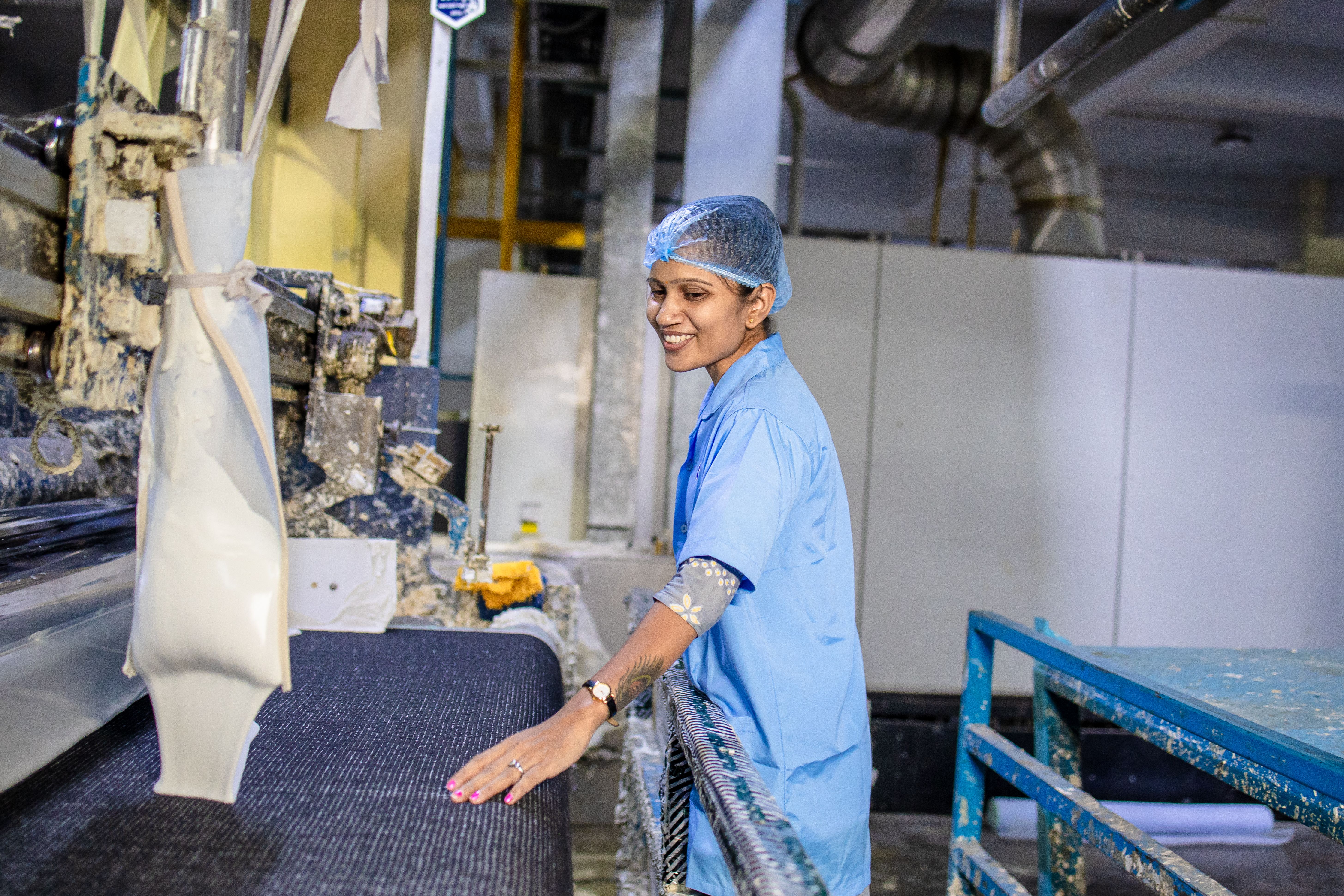 Smiling Female Factory Worker Operating Machinery · Free Stock Photo