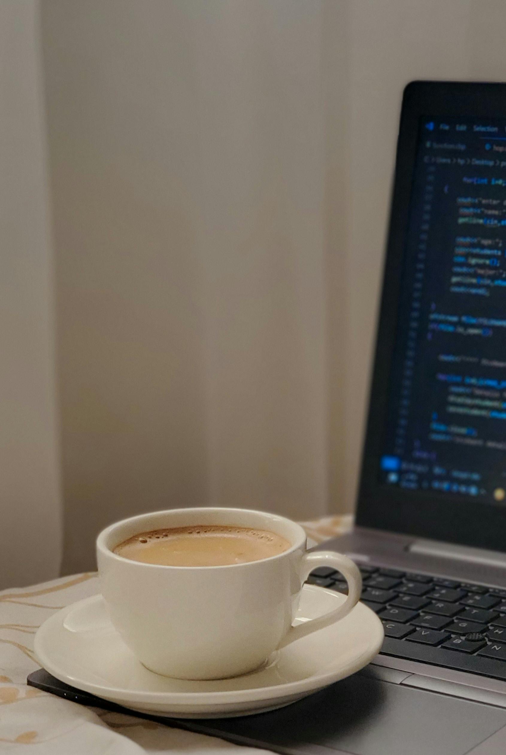 Cozy Workspace with Coffee and Coding Laptop · Free Stock Photo