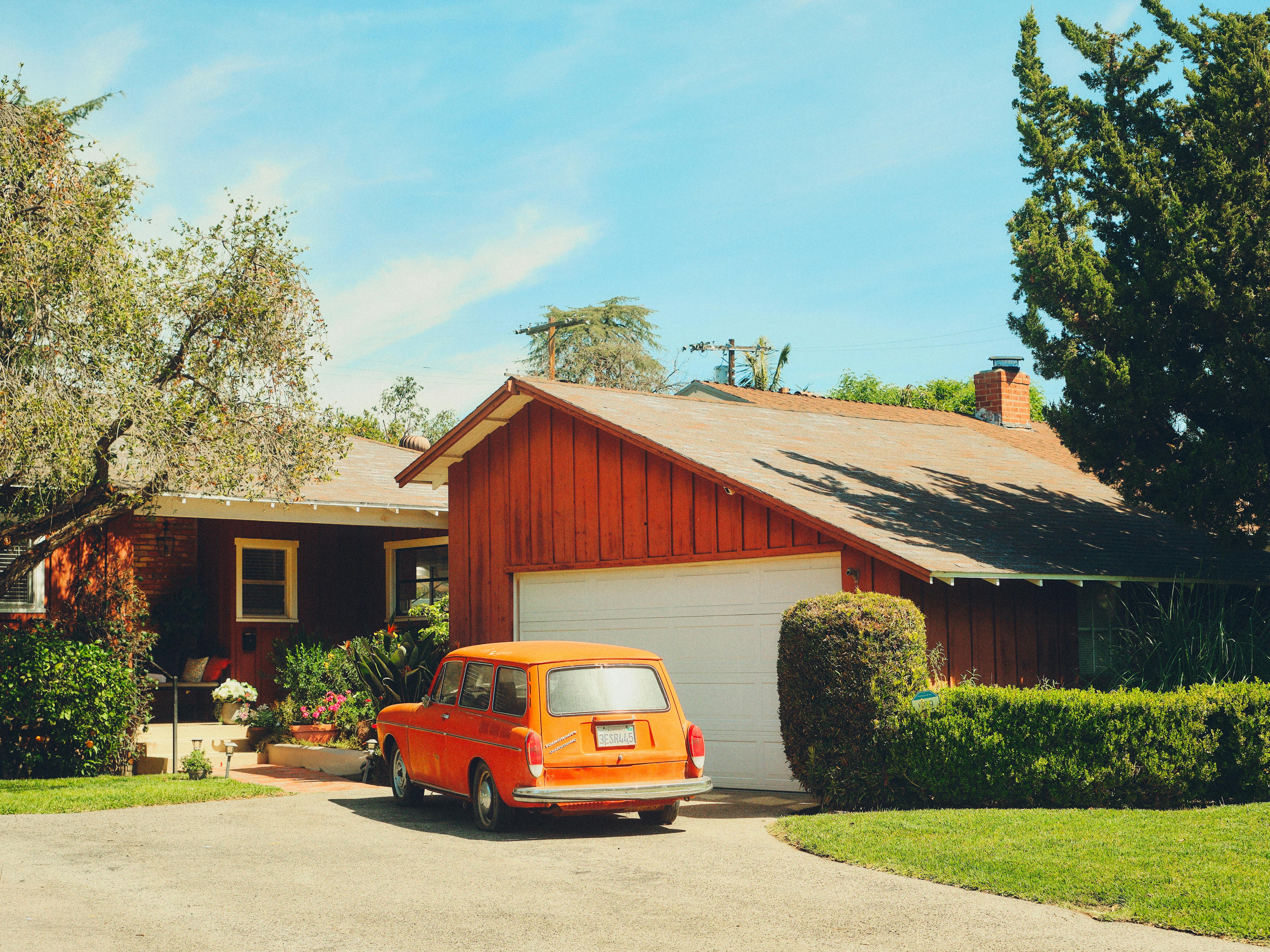 Vintage Orange Car Parked in Suburban Driveway · Free Stock Photo