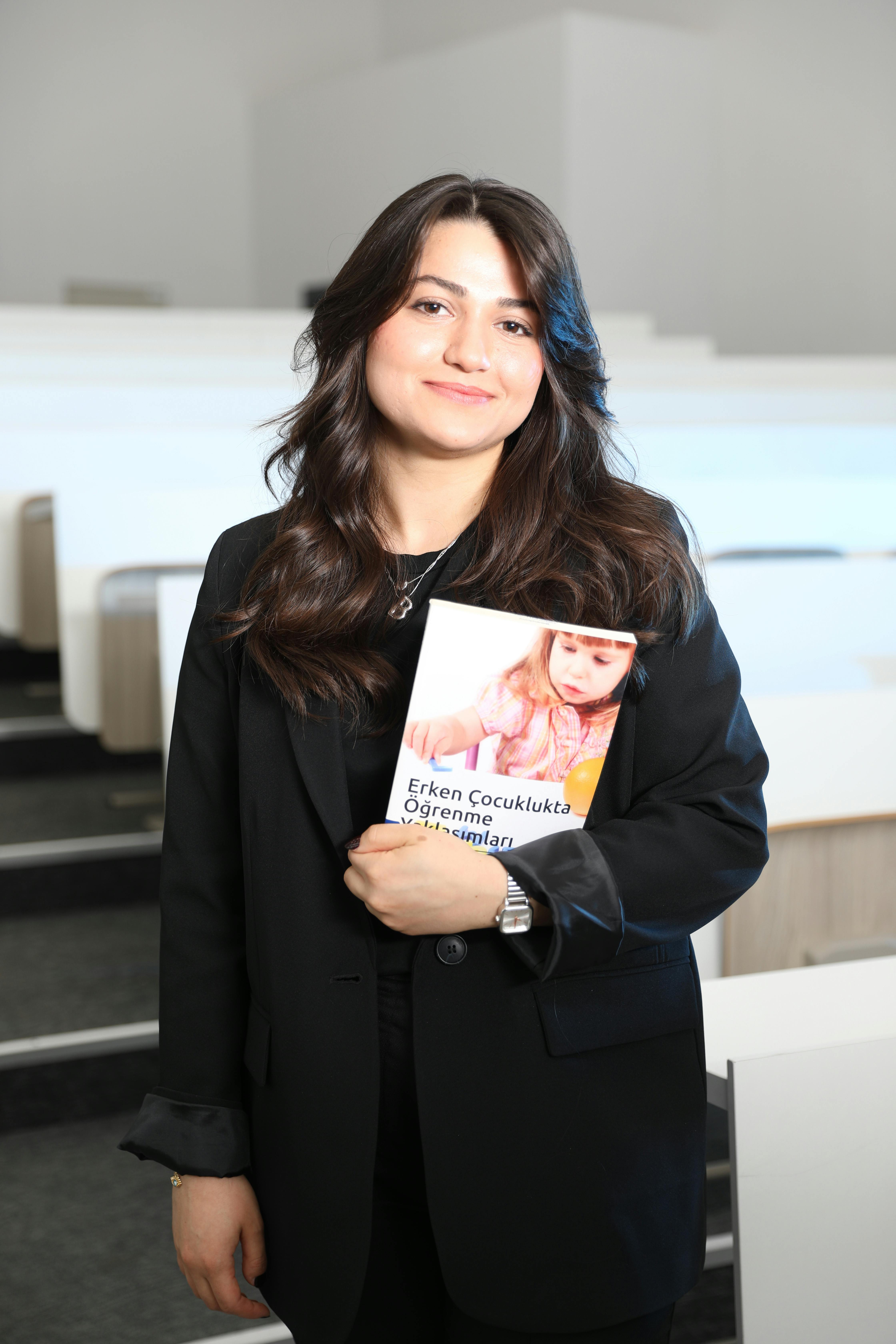 Smiling Woman Holding Educational Book in Lecture Hall · Free Stock Photo