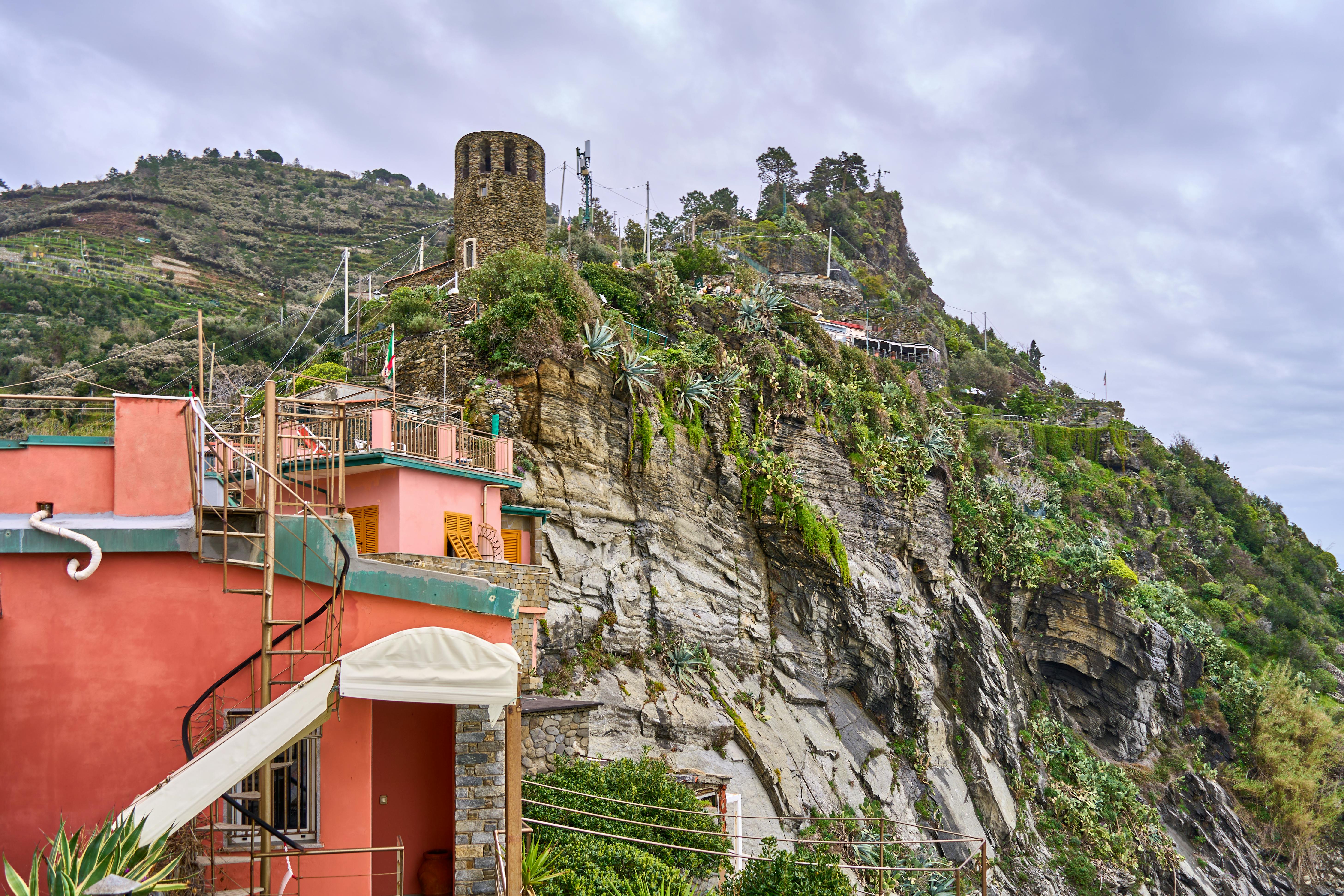 Colorful house and ancient tower on rocky cliffside · Free Stock Photo