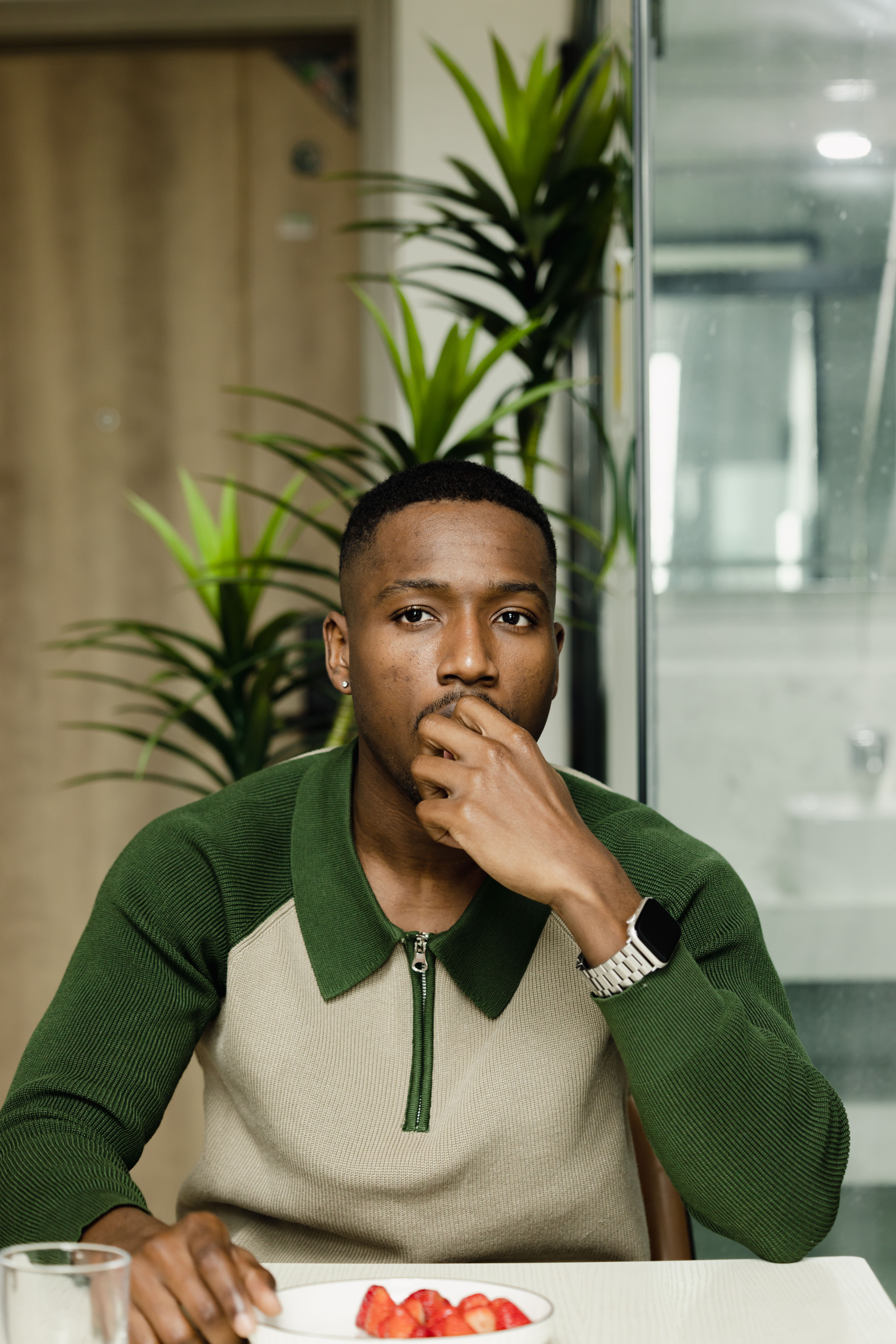 Thoughtful Man Seated Indoors with Plants · Free Stock Photo