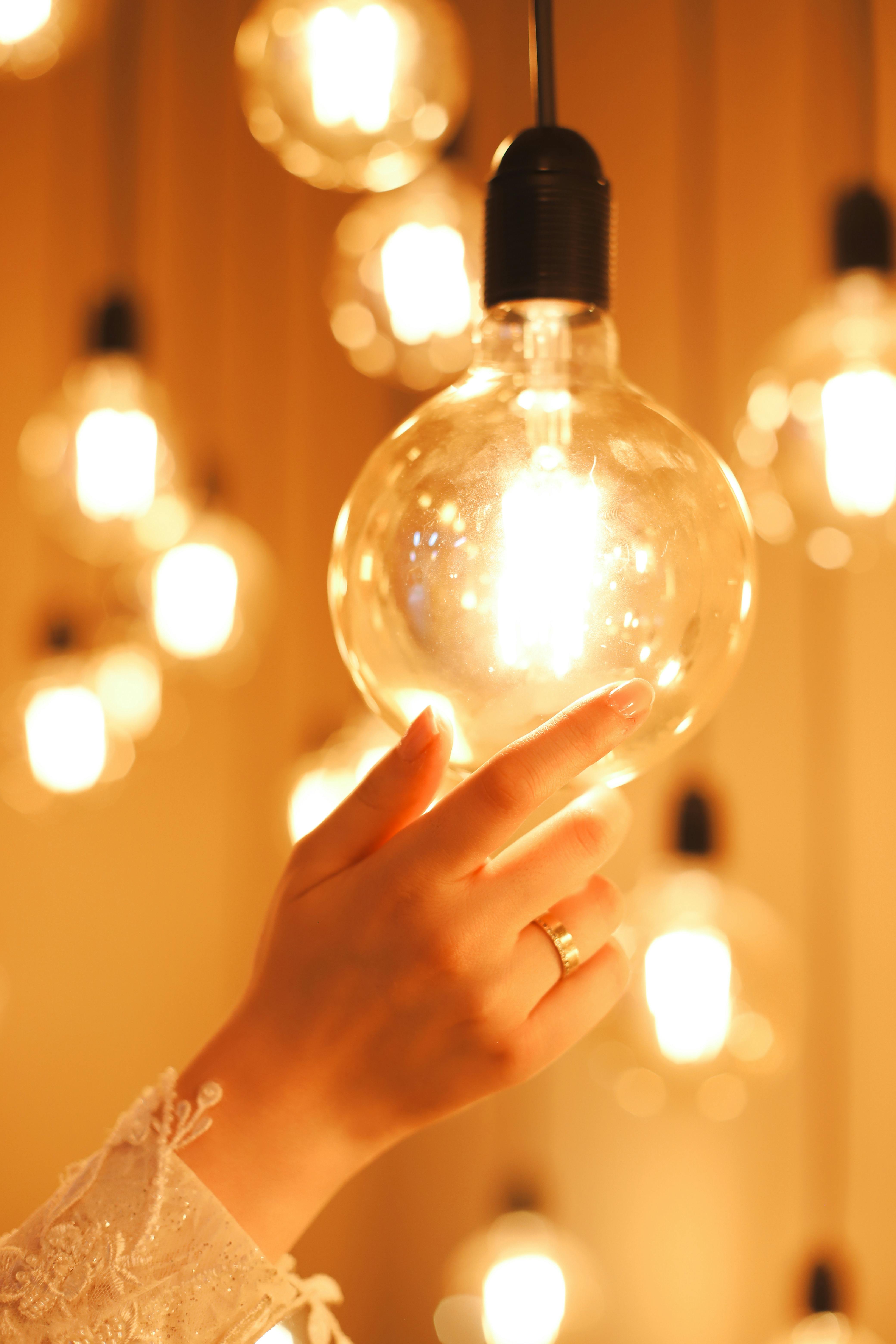 Hand Touching Glowing Light Bulb Closeup · Free Stock Photo