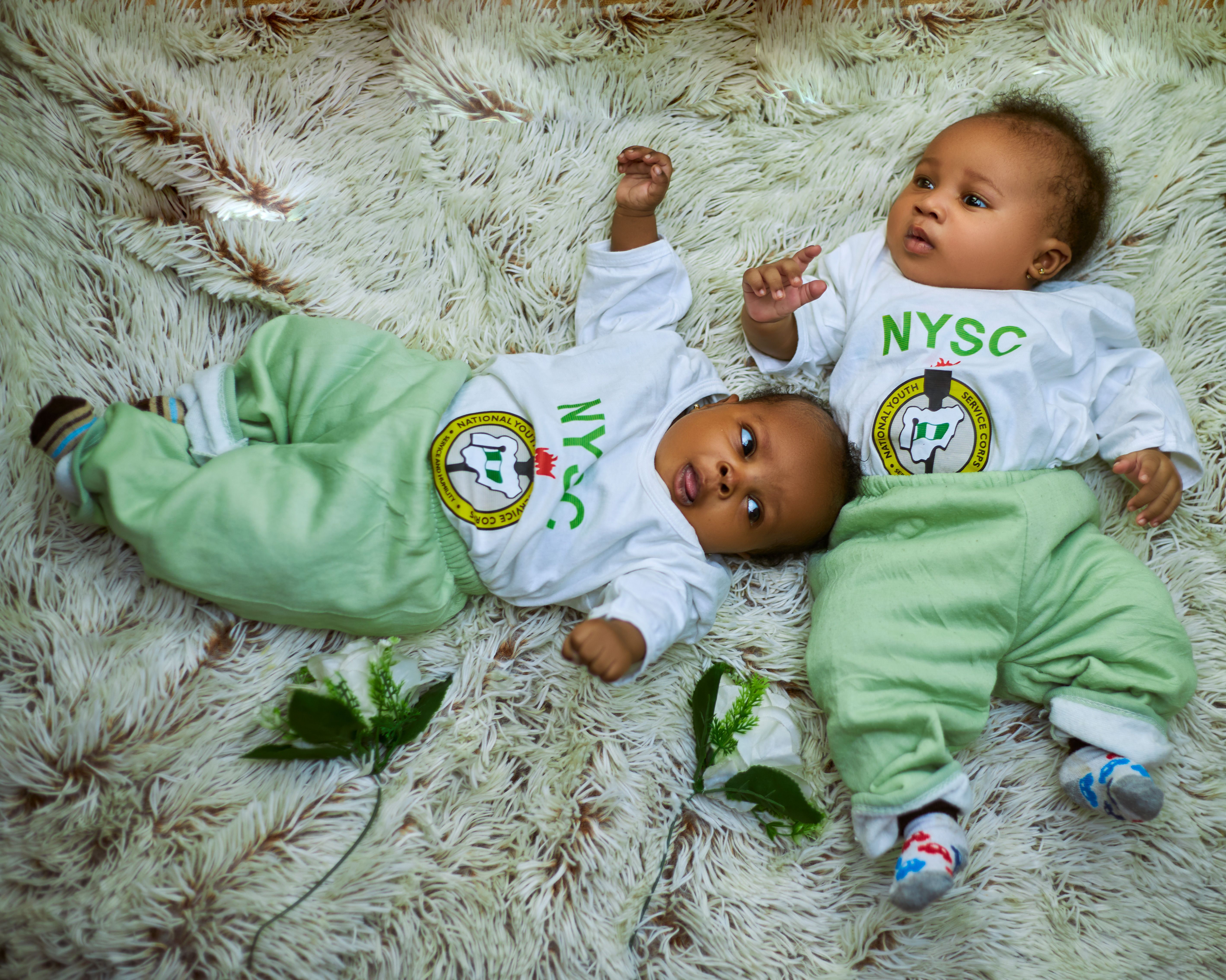 Cute Babies in NYSC Outfits on Soft Rug · Free Stock Photo