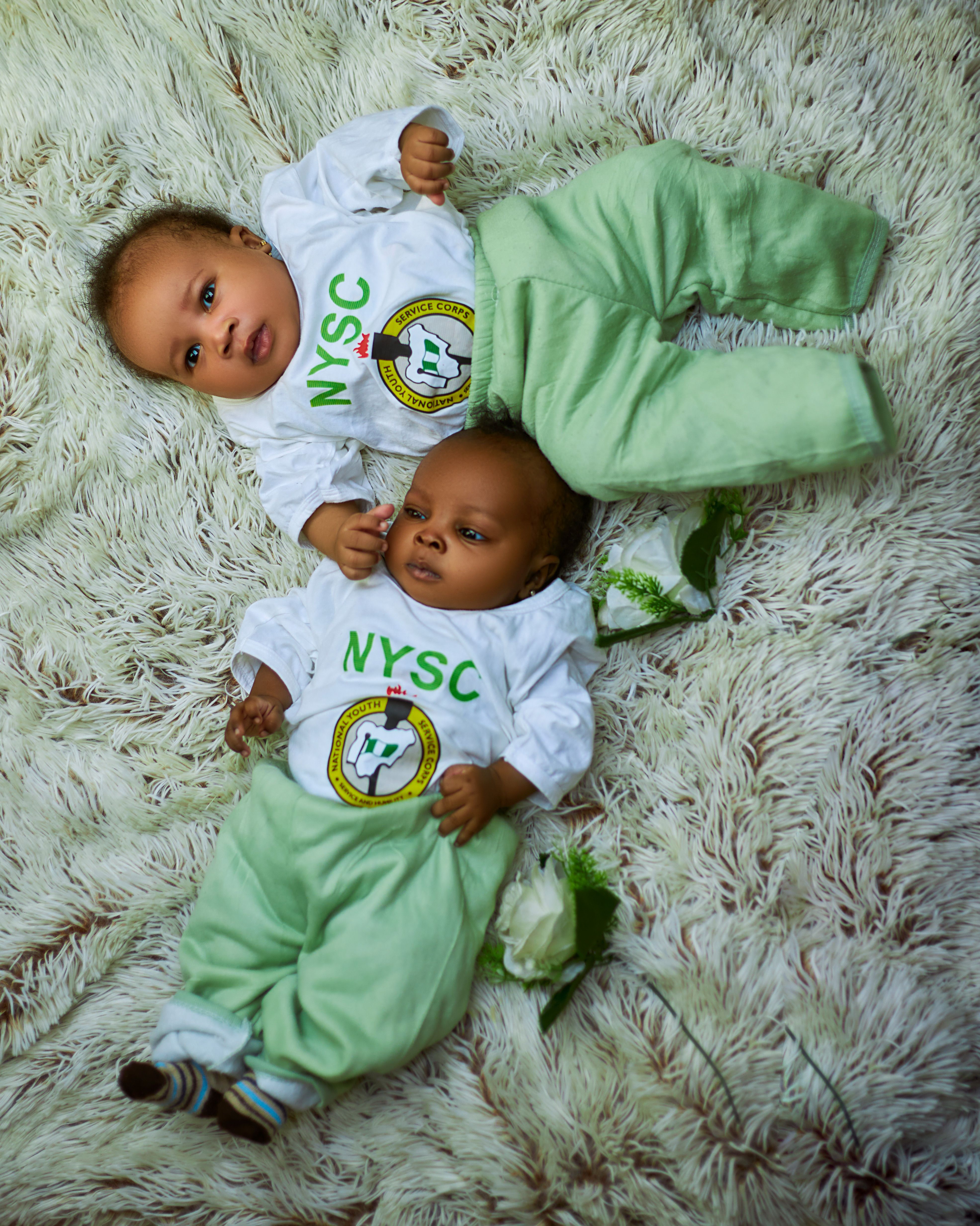 Adorable Babies in NYSC Attire on Carpet · Free Stock Photo