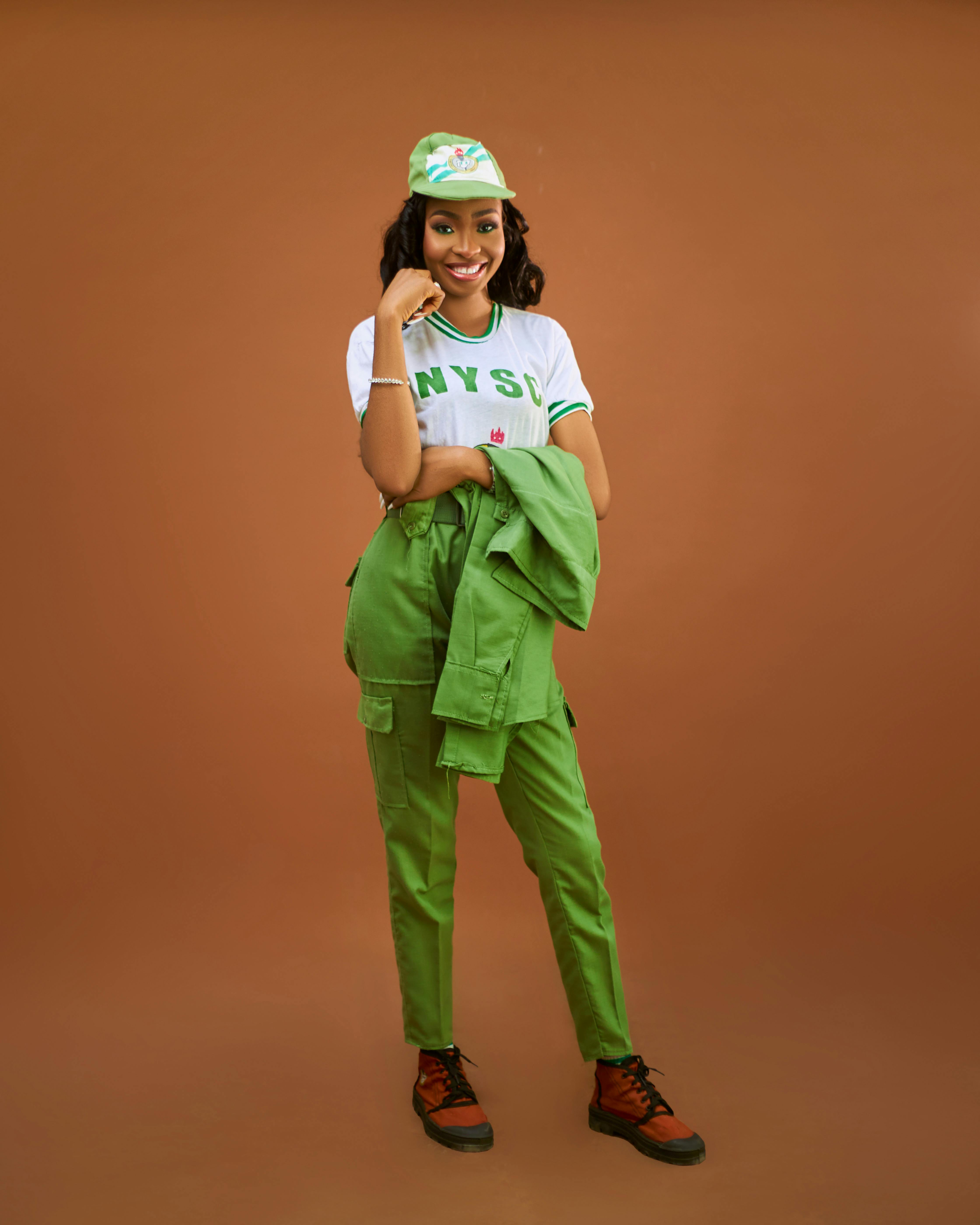 Female Youth in NYSC Uniform Against Brown Background · Free Stock Photo