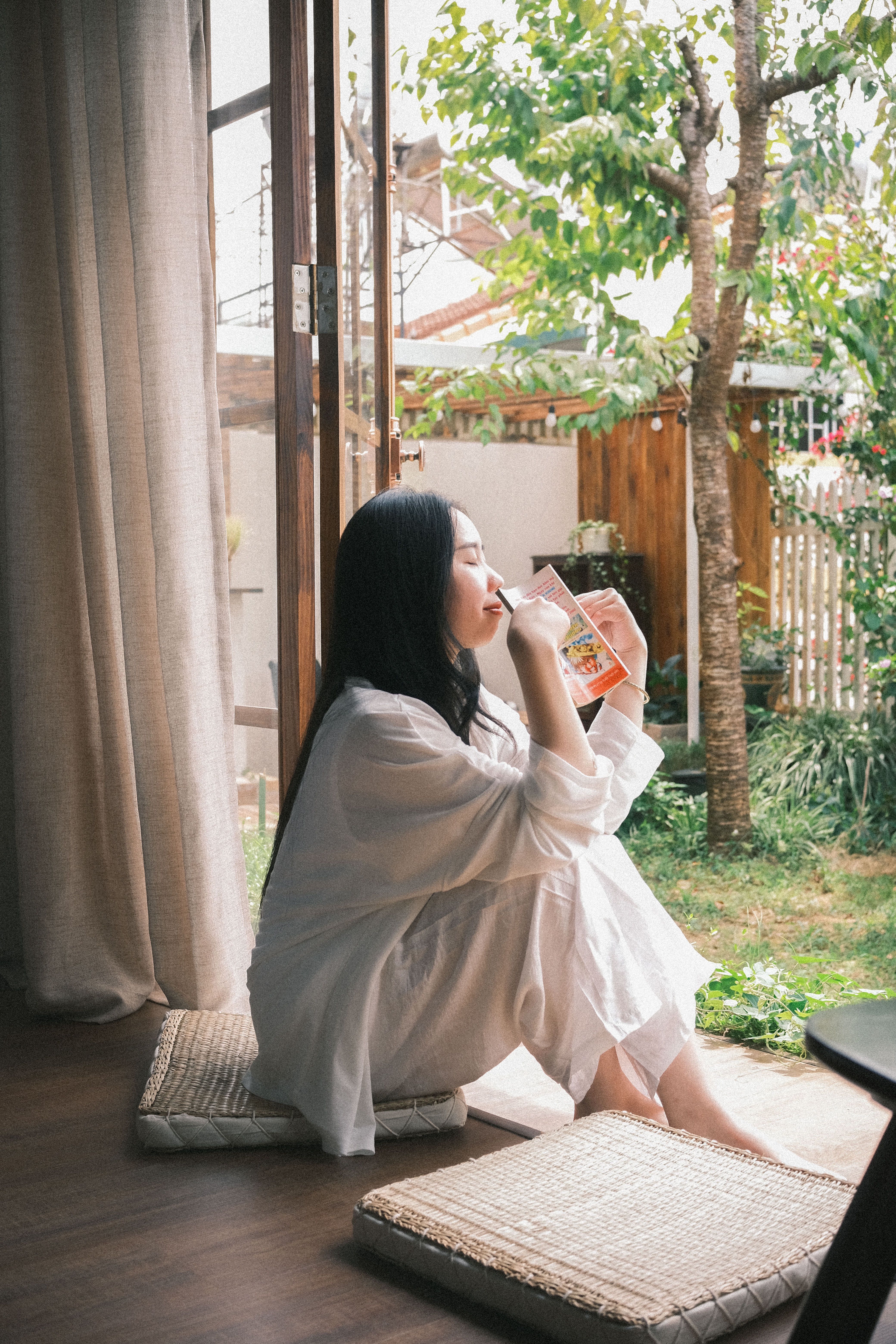 Young Woman Relaxing with Tea by Open Window · Free Stock Photo
