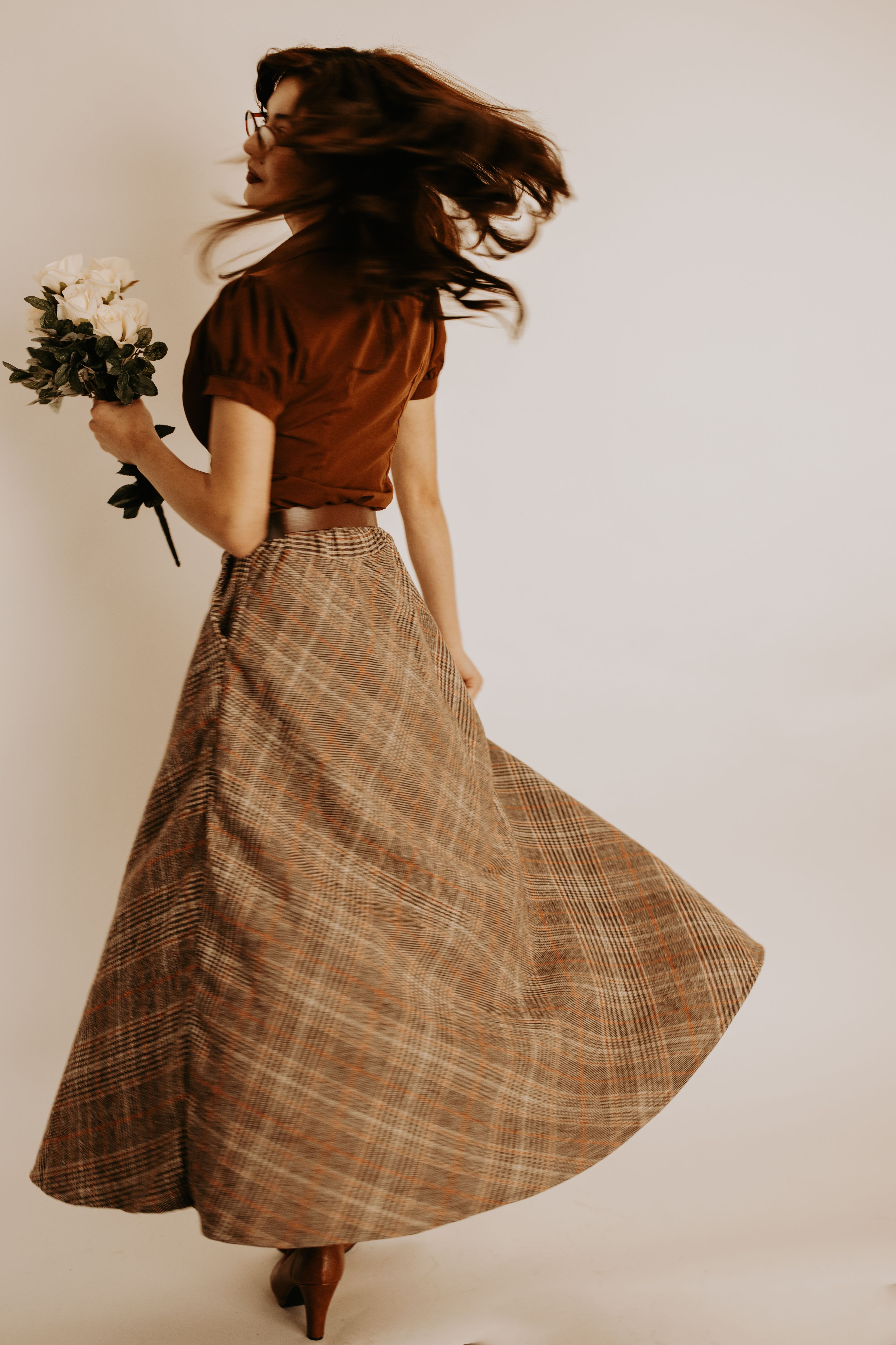 Woman Twirling in Plaid Skirt with Roses · Free Stock Photo