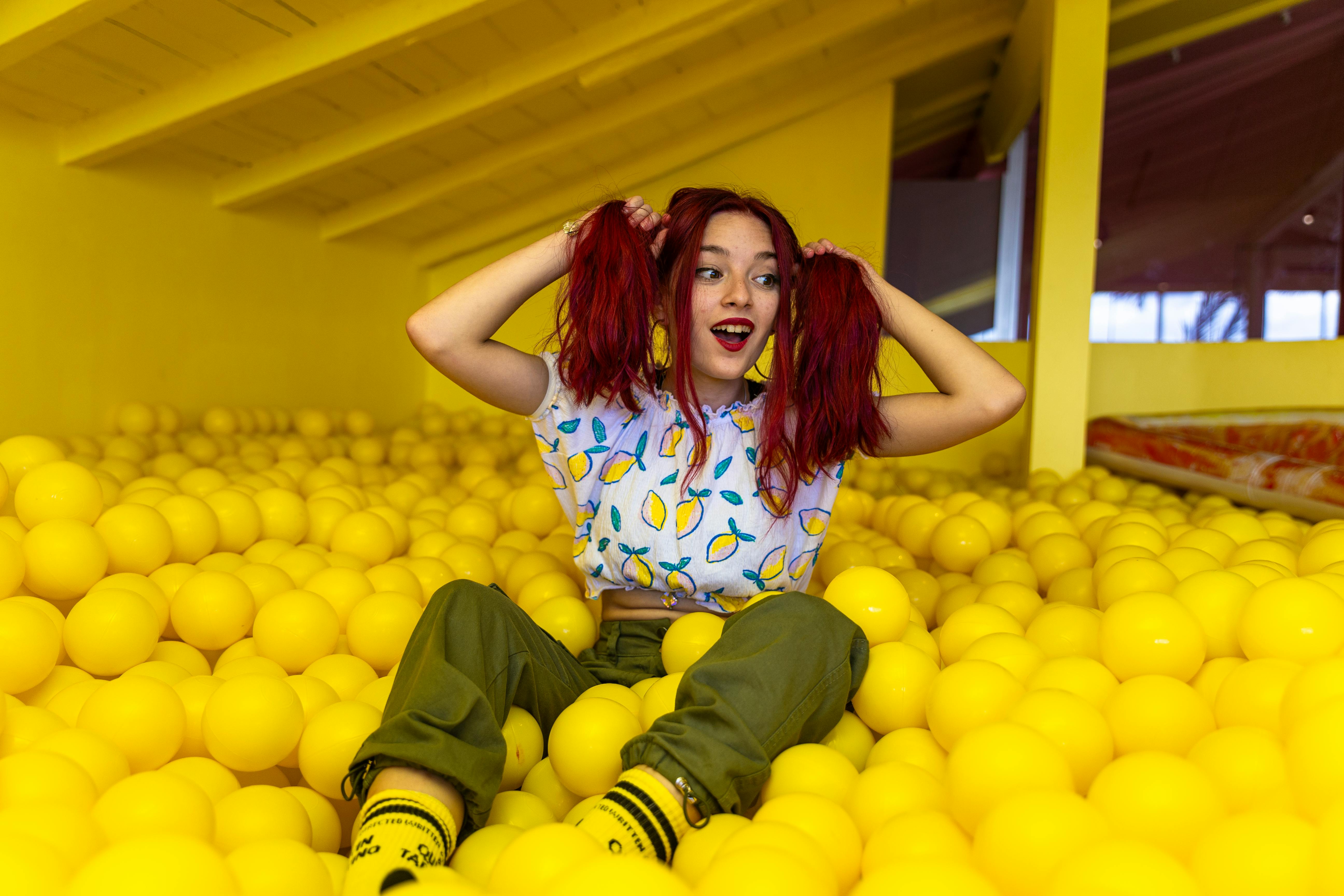 Playful Girl in Yellow Ball Pit with Red Hair · Free Stock Photo
