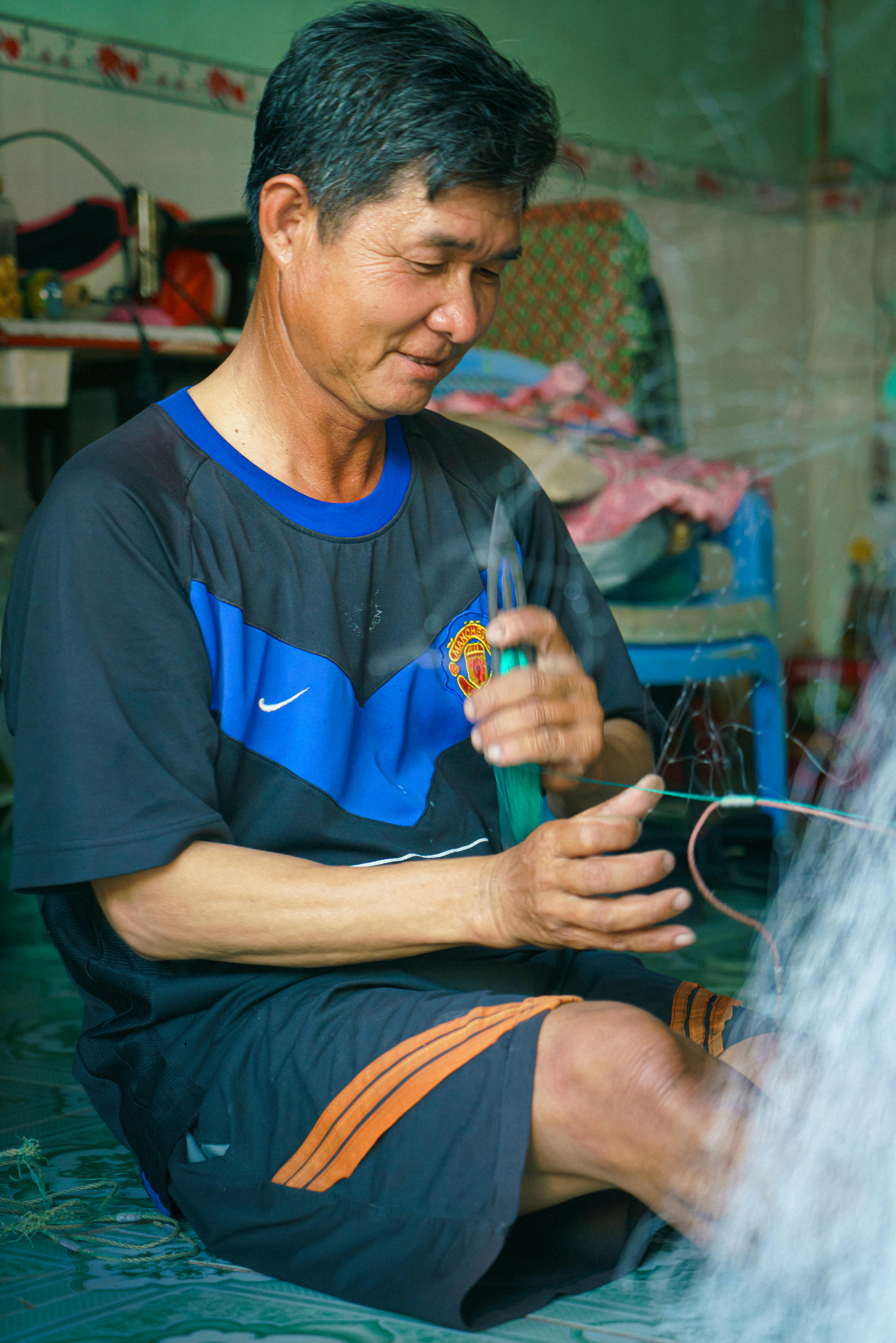 Vietnamese Fisherman Weaving Nets in Workshop · Free Stock Photo