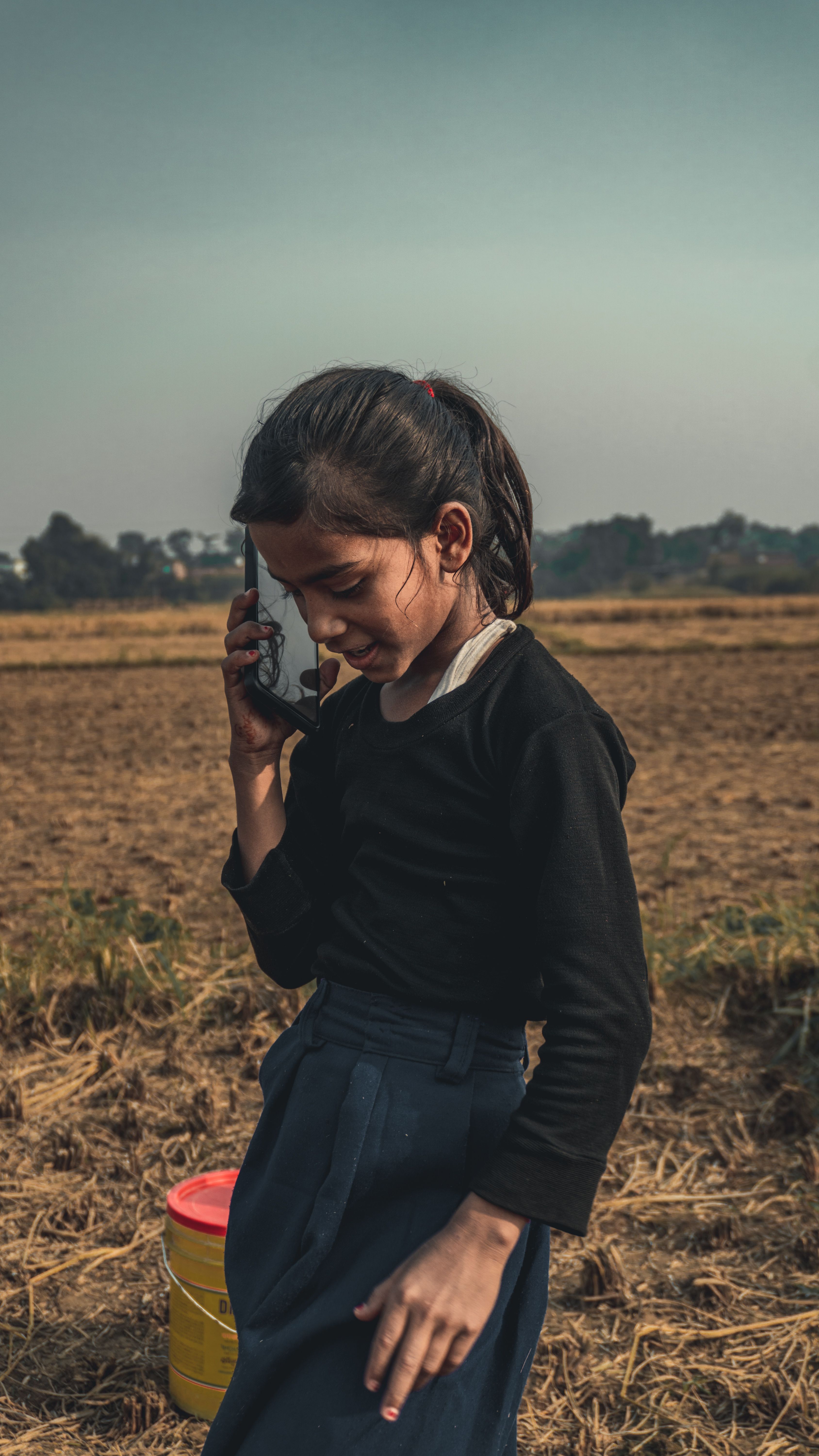Girl Talking on Phone in Rural Field Setting · Free Stock Photo