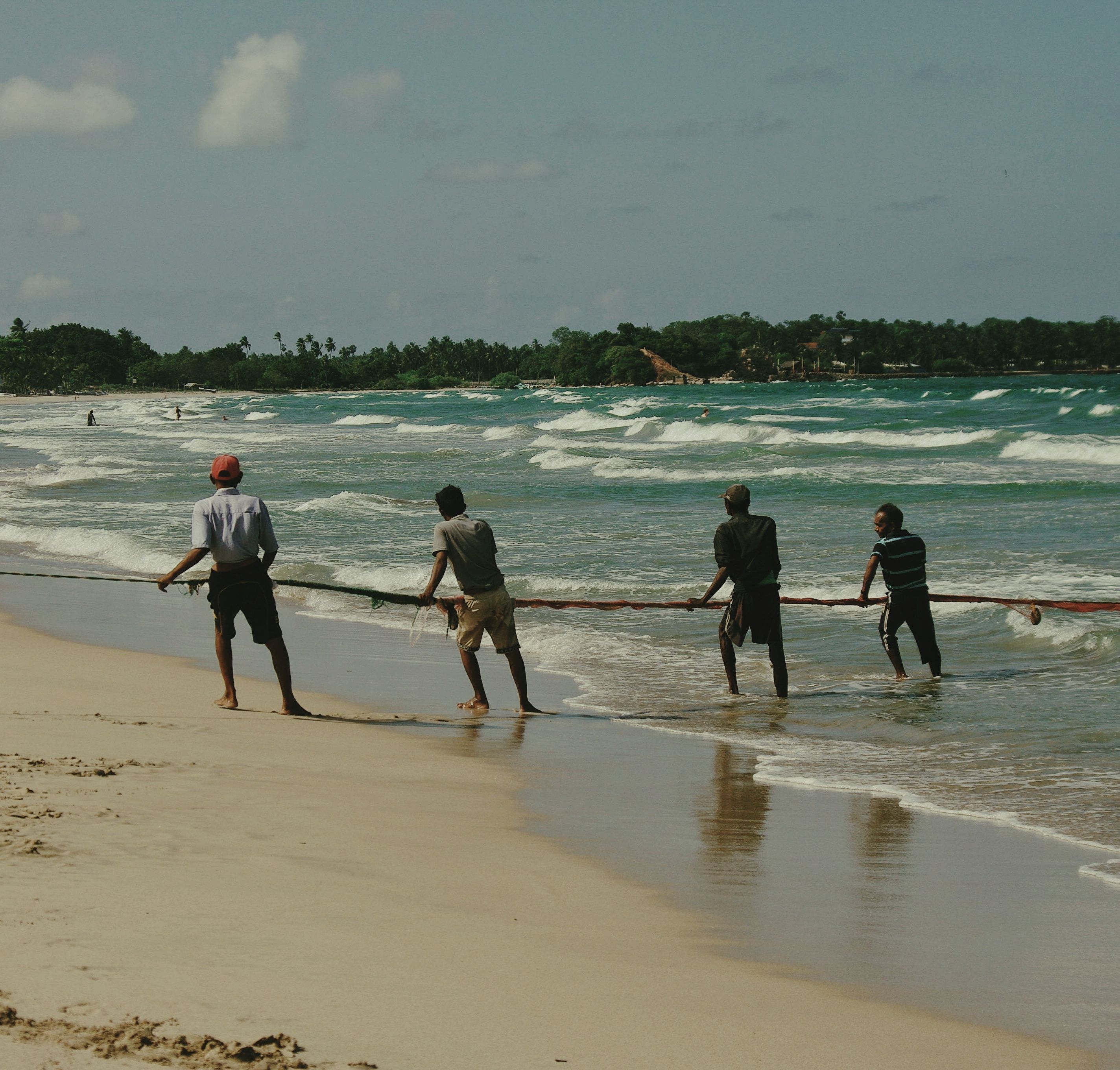 Fishermen at Work on Tropical Beach Shoreline · Free Stock Photo