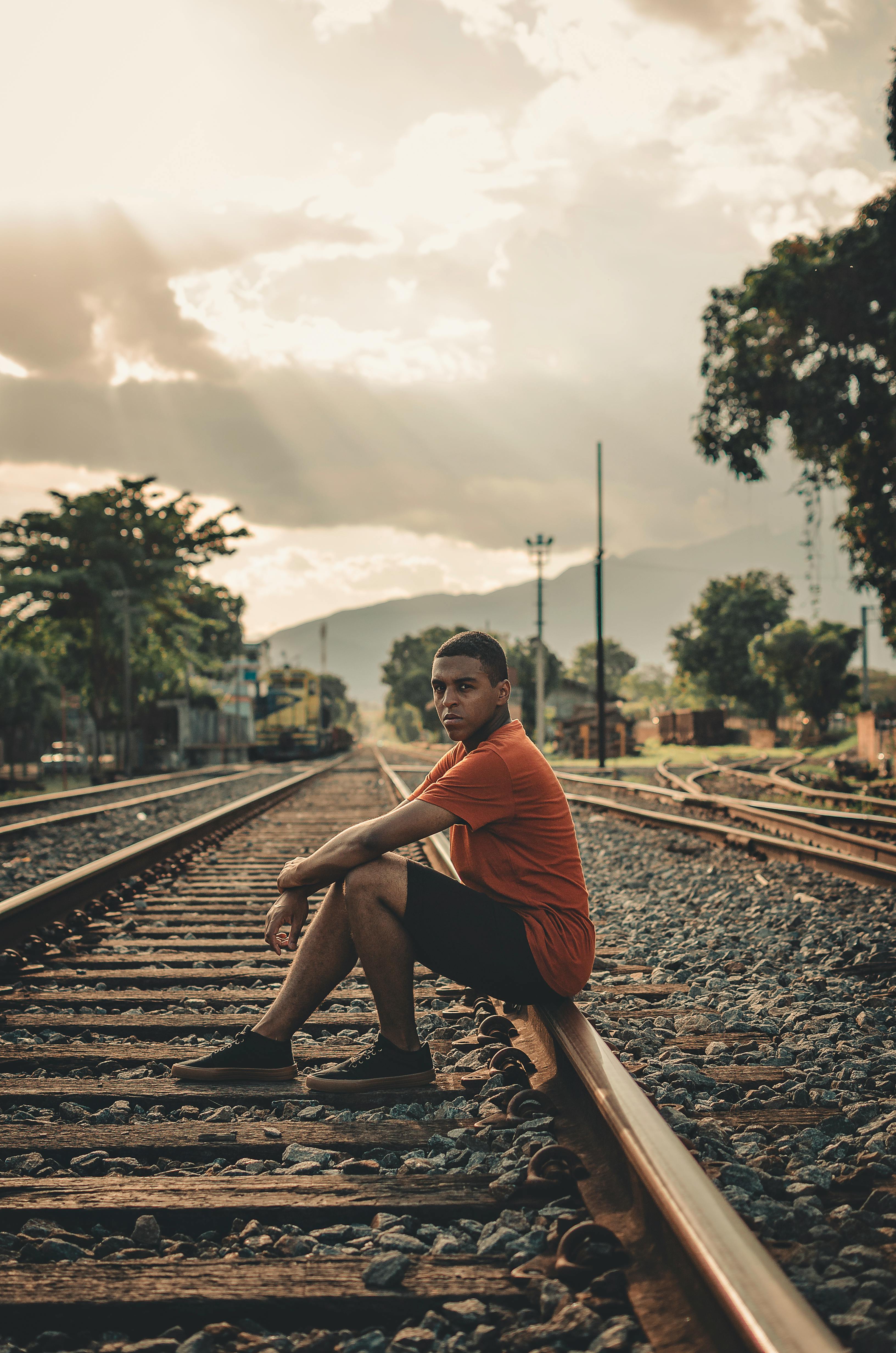 Man Sitting on Railroad during Day · Free Stock Photo