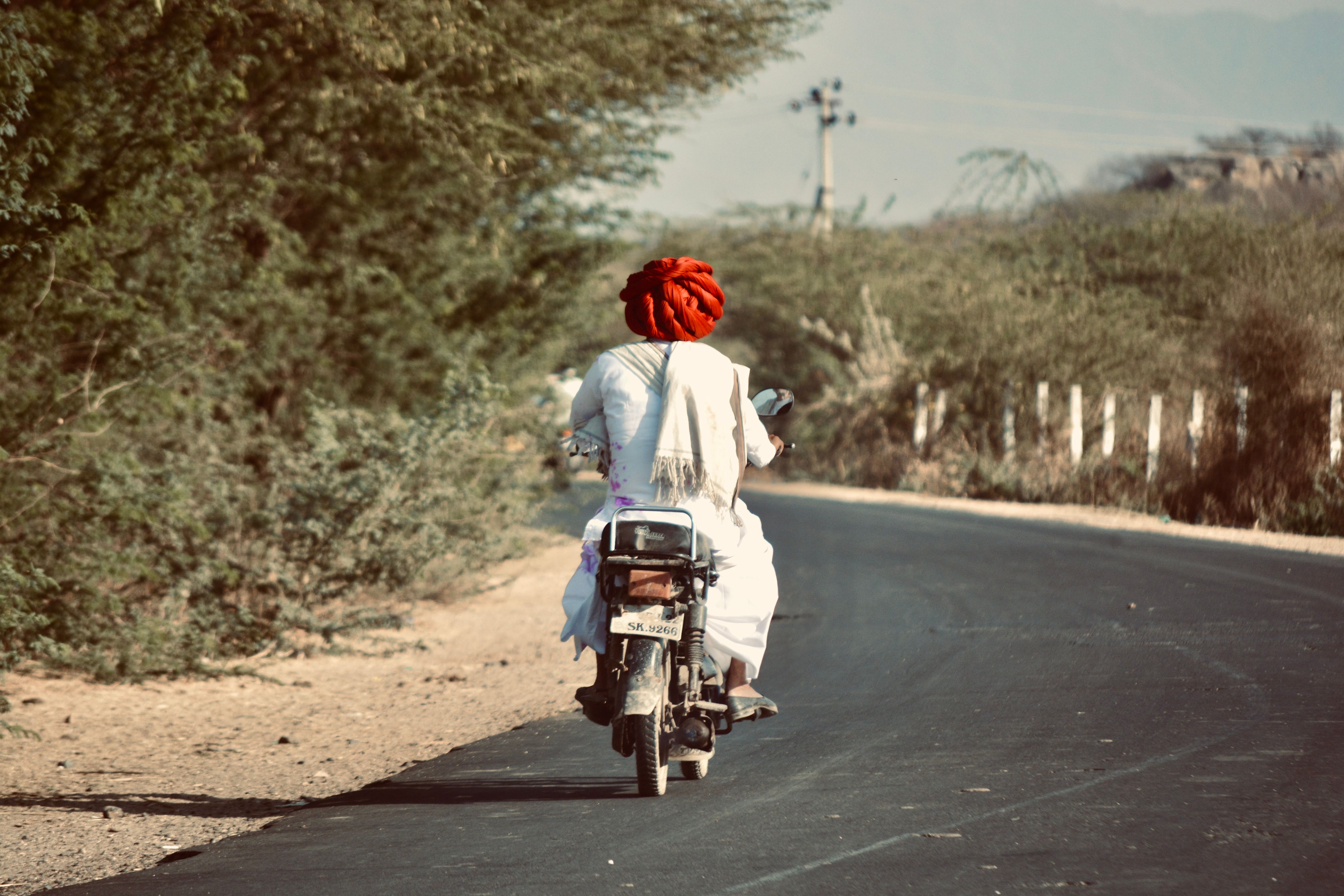 Rural Indian Man Riding Motorcycle on Desert Road · Free Stock Photo