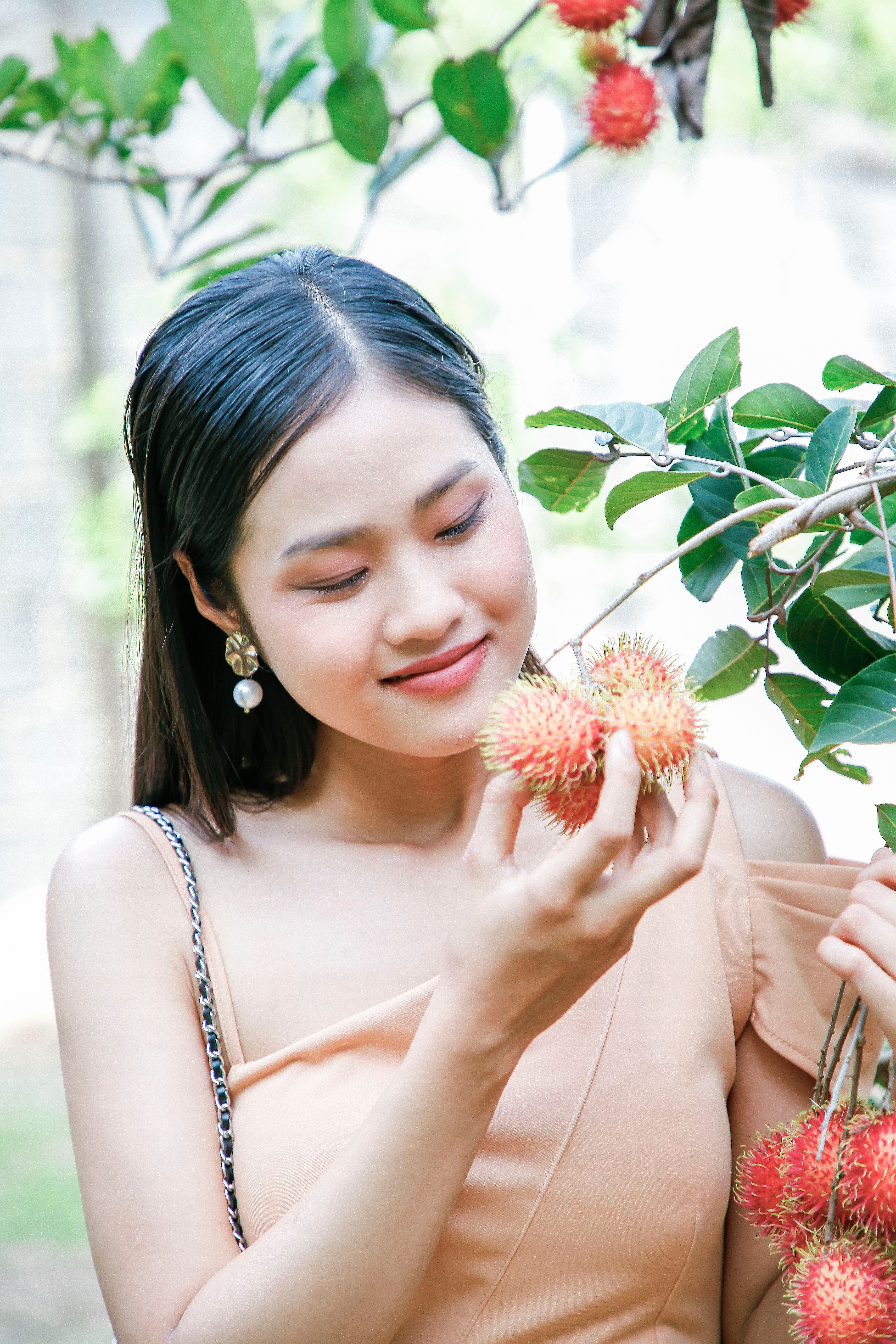 Young Woman Enjoying Fresh Ripe Rambutan Outdoors · Free Stock Photo