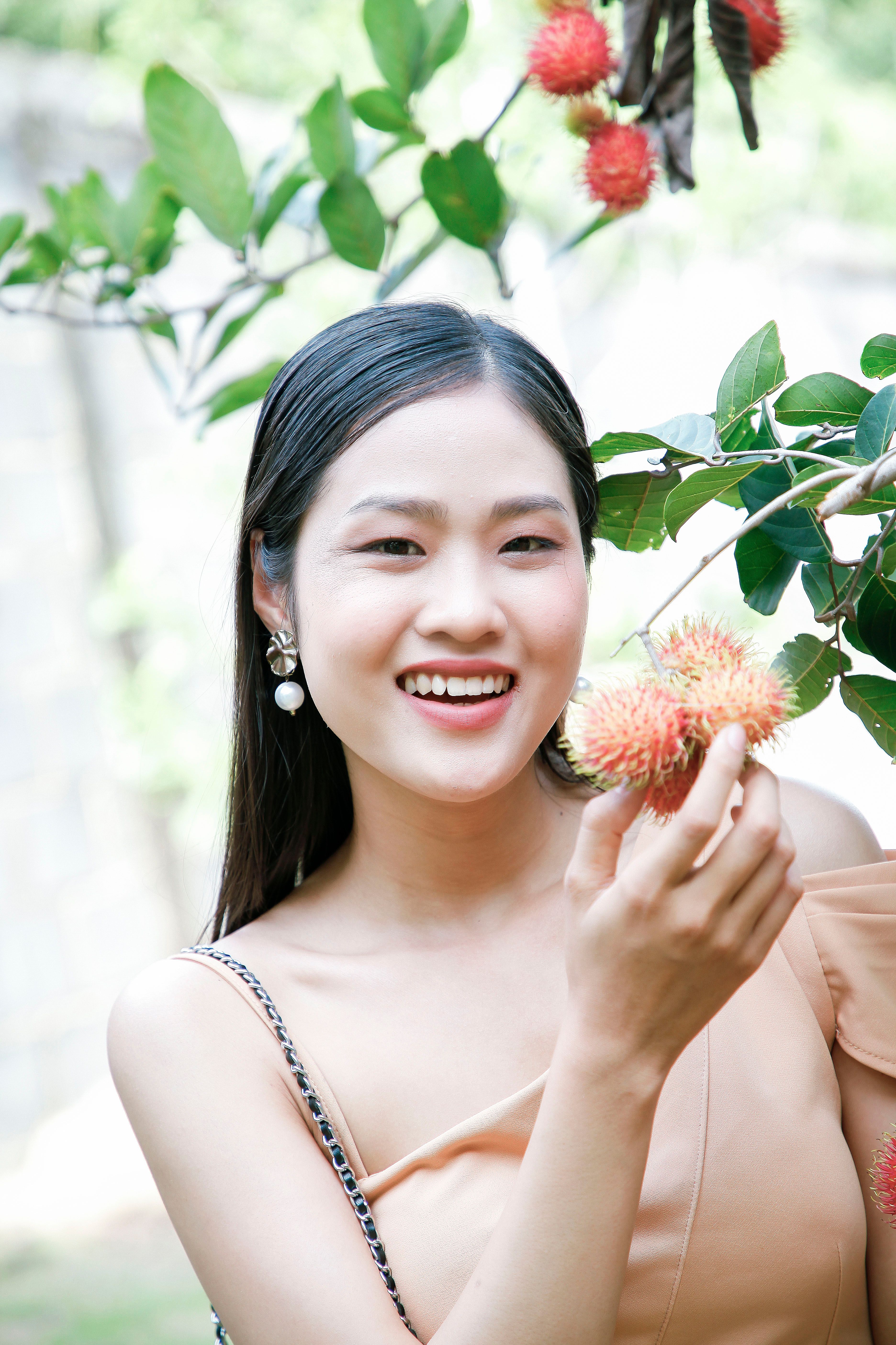 Young Woman Enjoying Fresh Rambutans Outdoors · Free Stock Photo