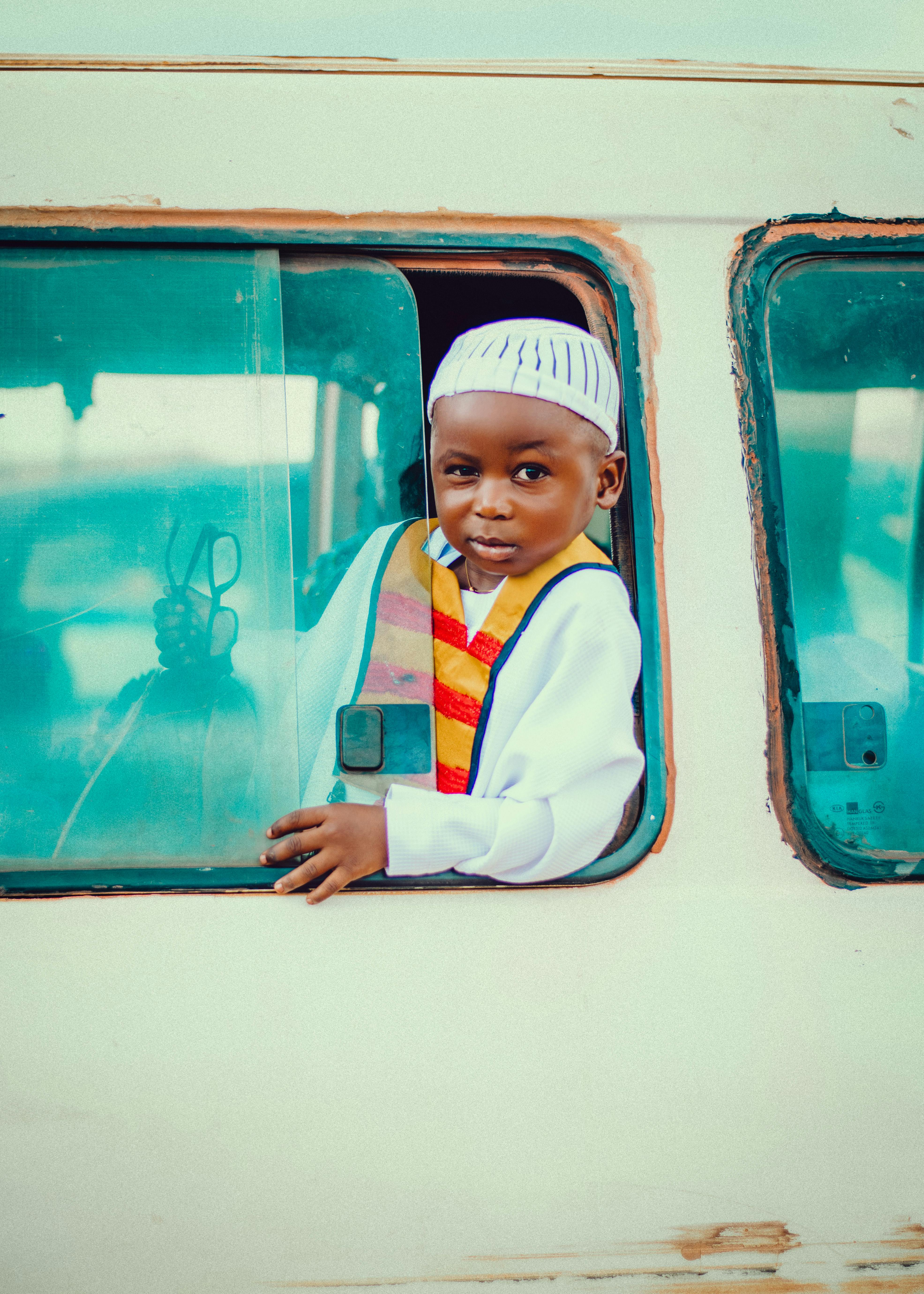 Young Boy Looking Out Van Window in Traditional Attire · Free Stock Photo