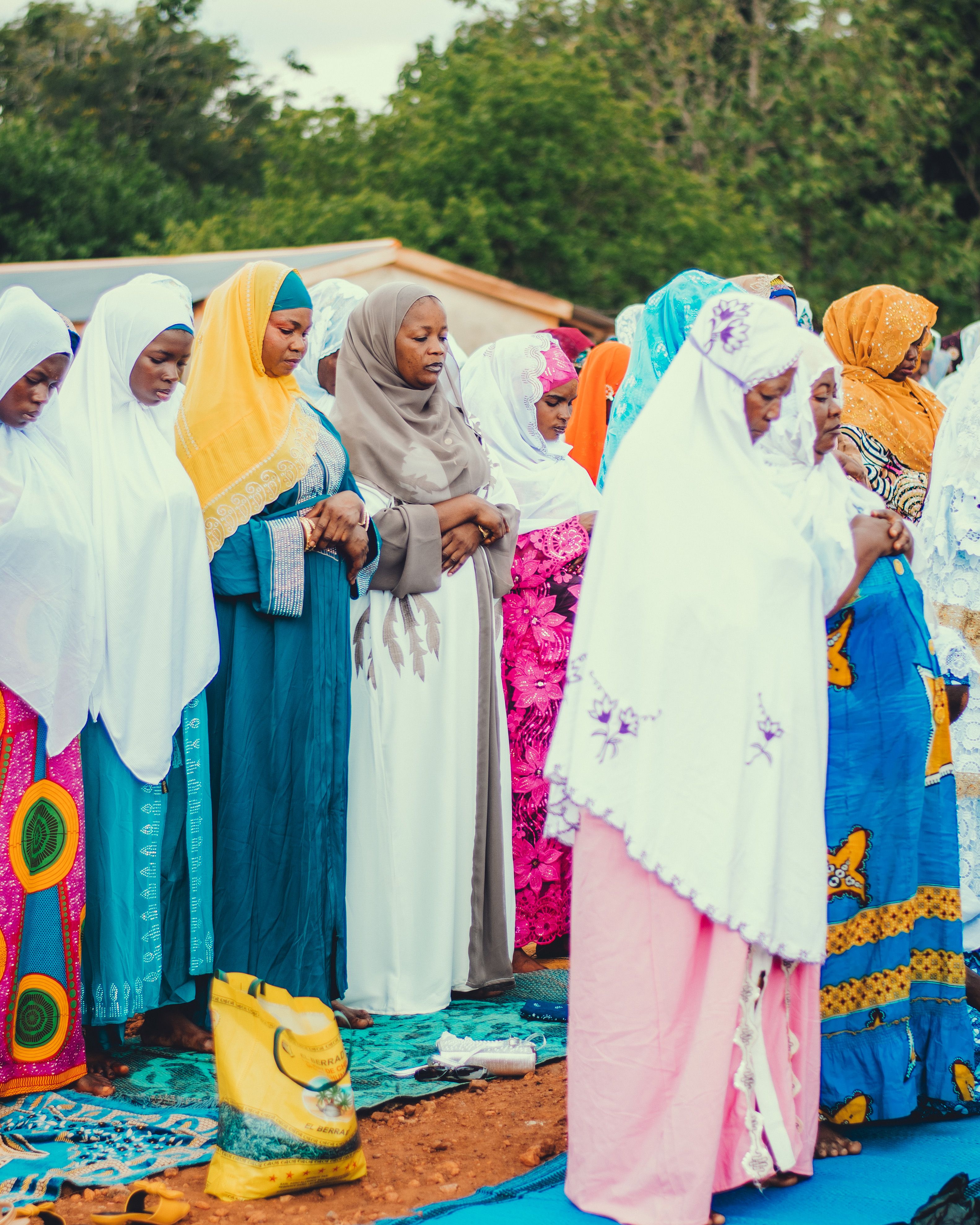 Muslim Women Praying Outdoors in Colorful Attire · Free Stock Photo