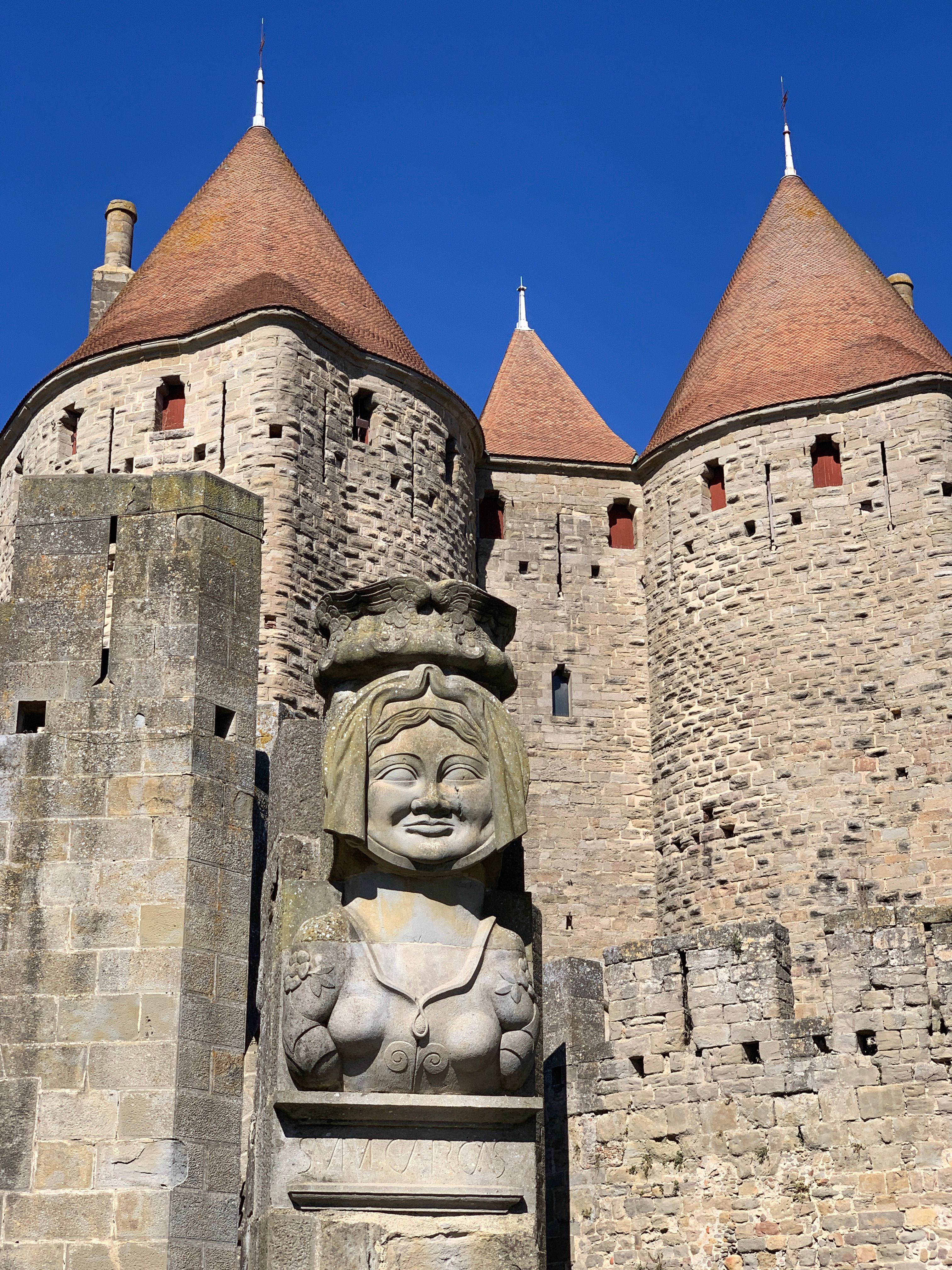Historic Castle with Carved Stone Statue Under Blue Sky · Free Stock Photo