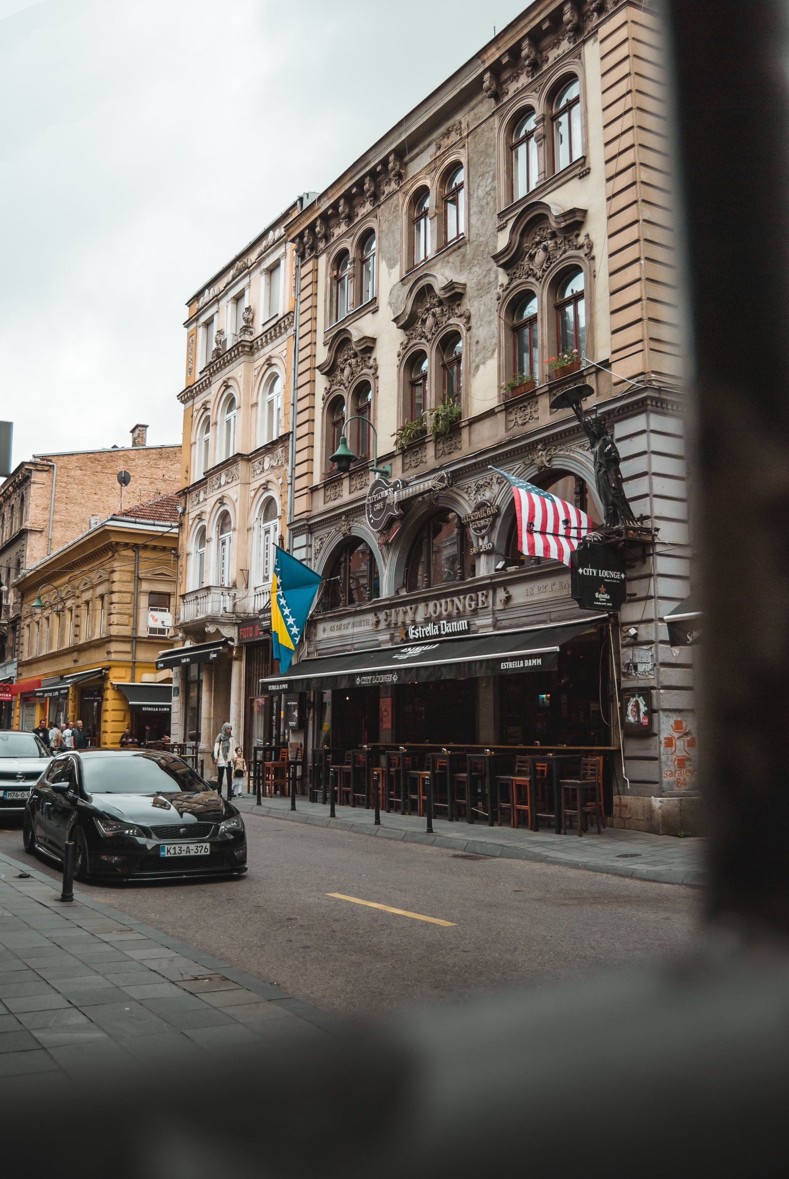 Historic European Street with Flags and Café · Free Stock Photo