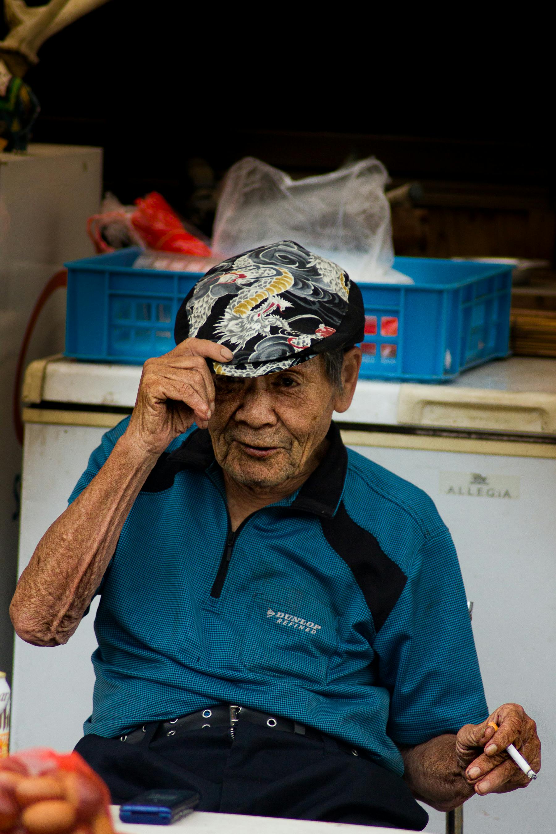 Elderly man tipping patterned cap in casual setting · Free Stock Photo