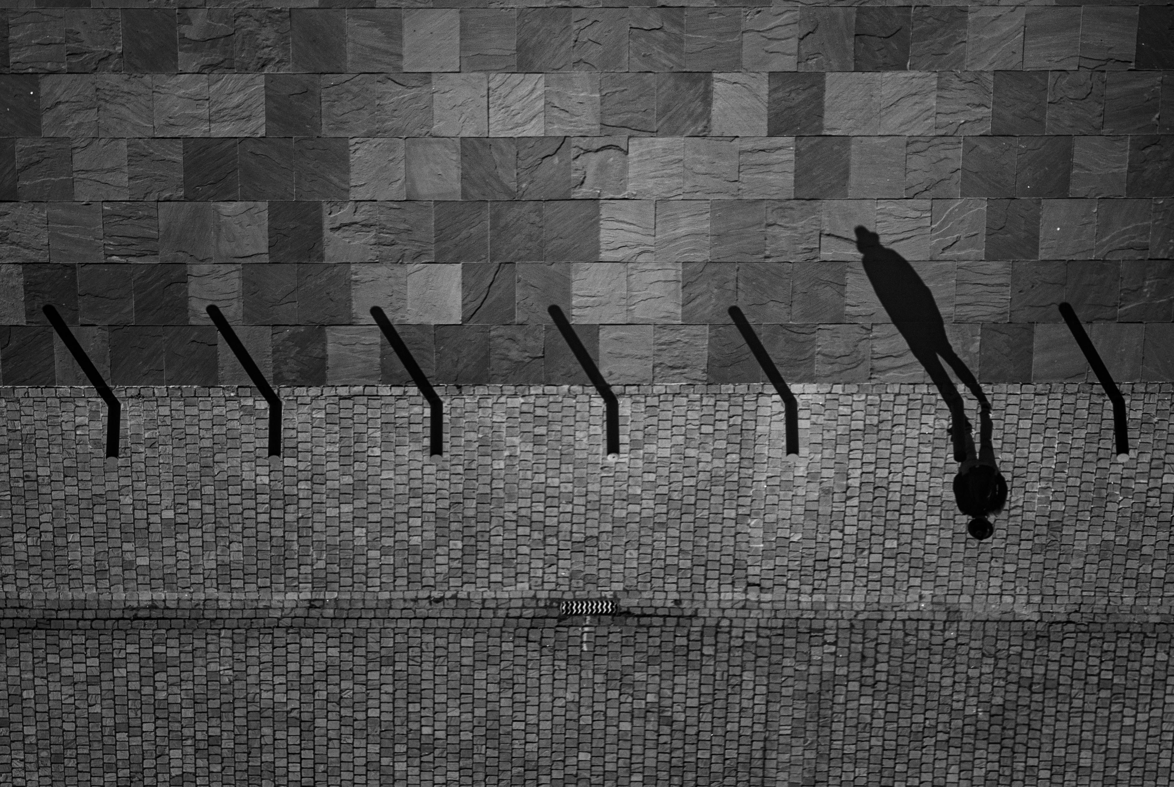 Aerial View of Person Walking with Shadow on Cobblestone · Free Stock Photo