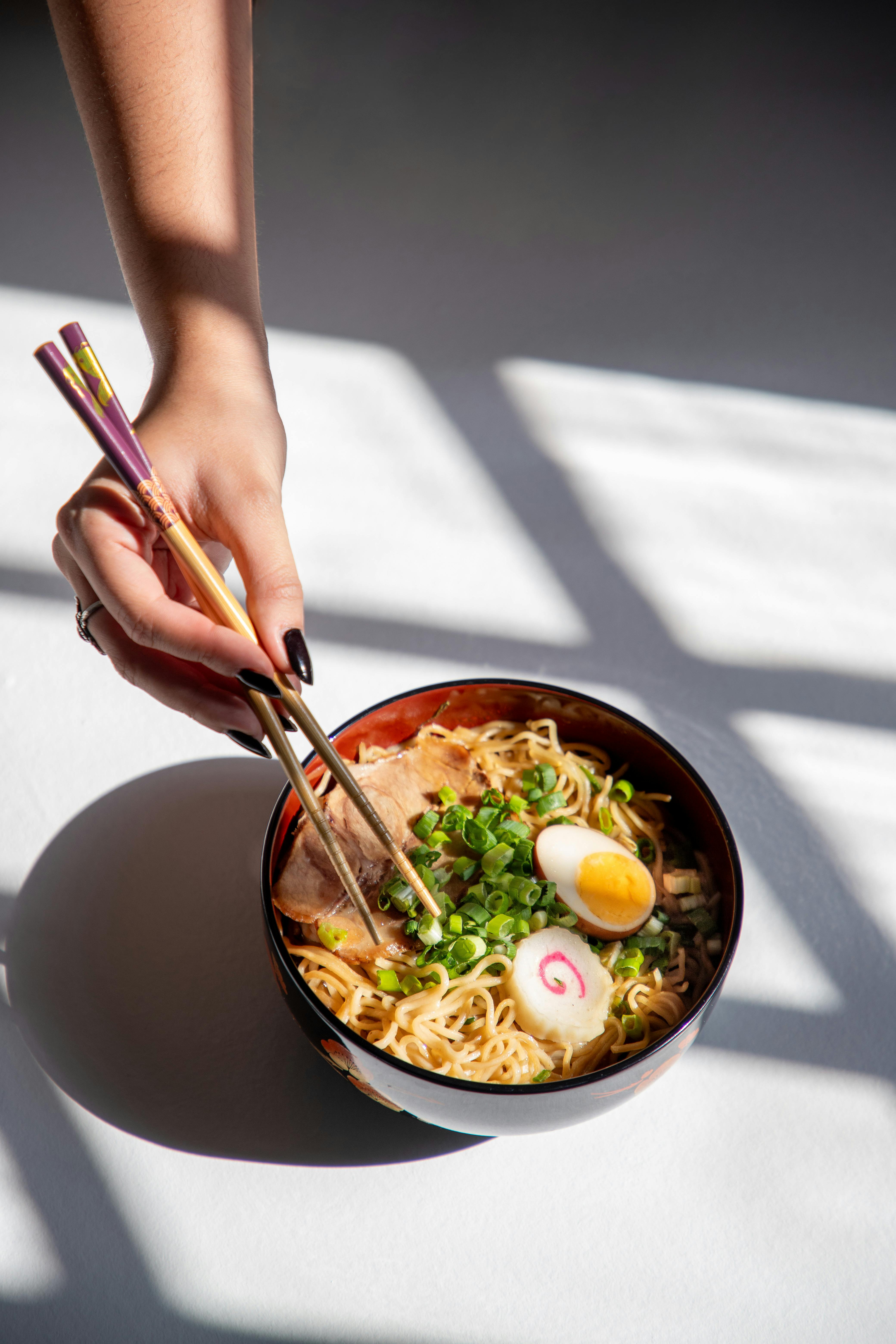 Hand using chopsticks with ramen bowl · Free Stock Photo