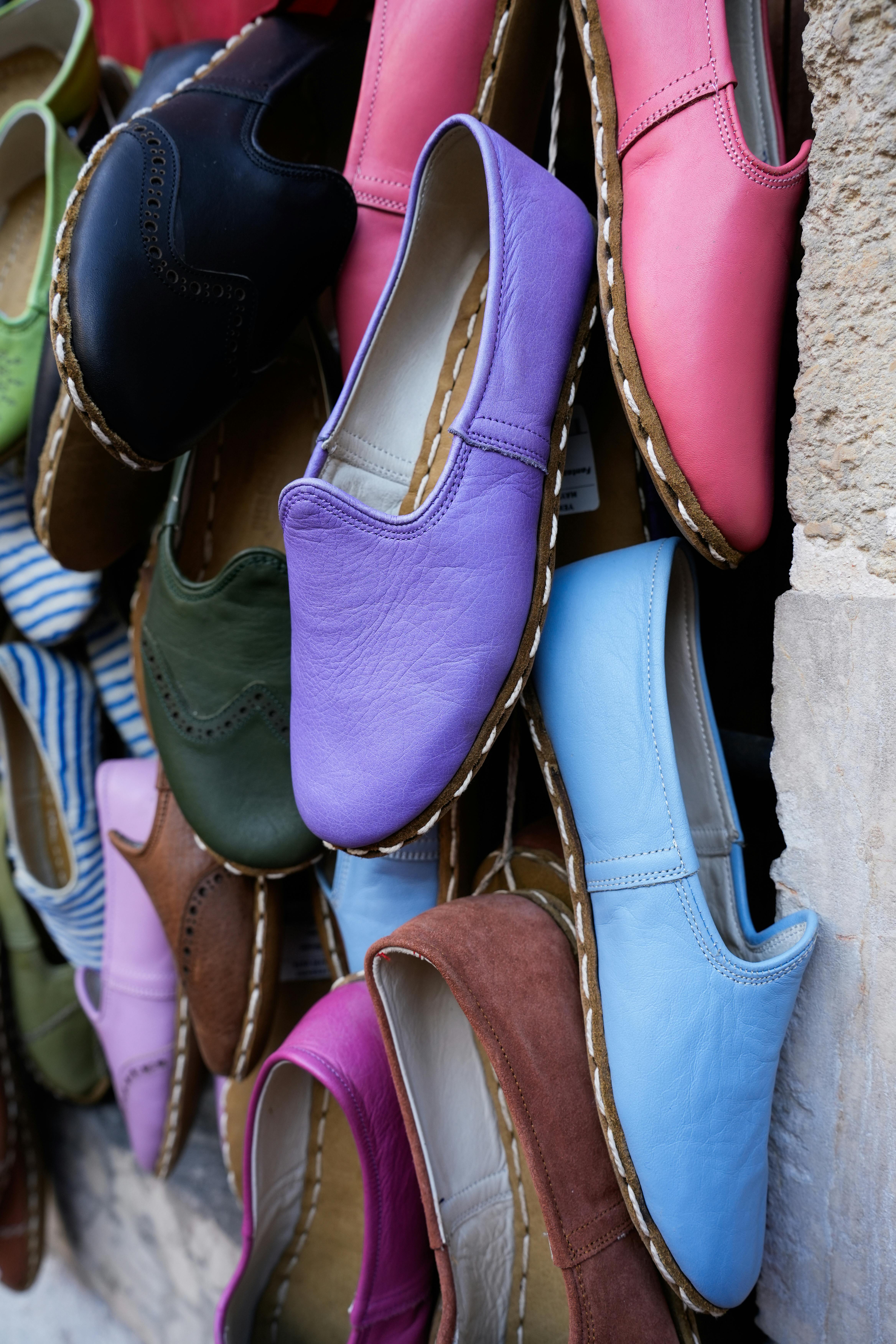 Colorful Leather Shoes Display on Stone Wall · Free Stock Photo