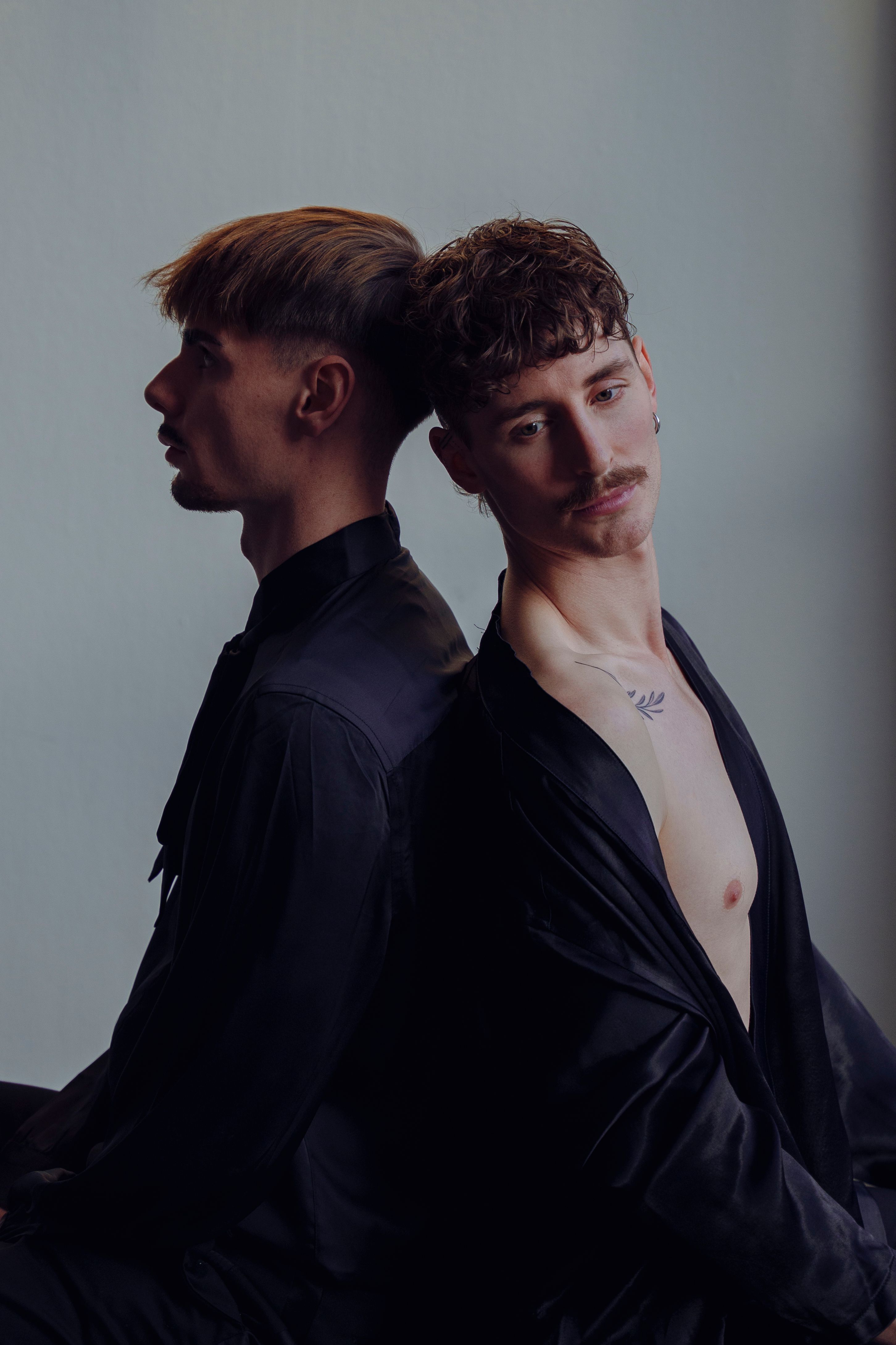 Two Men in Black Clothing Posing Back to Back · Free Stock Photo