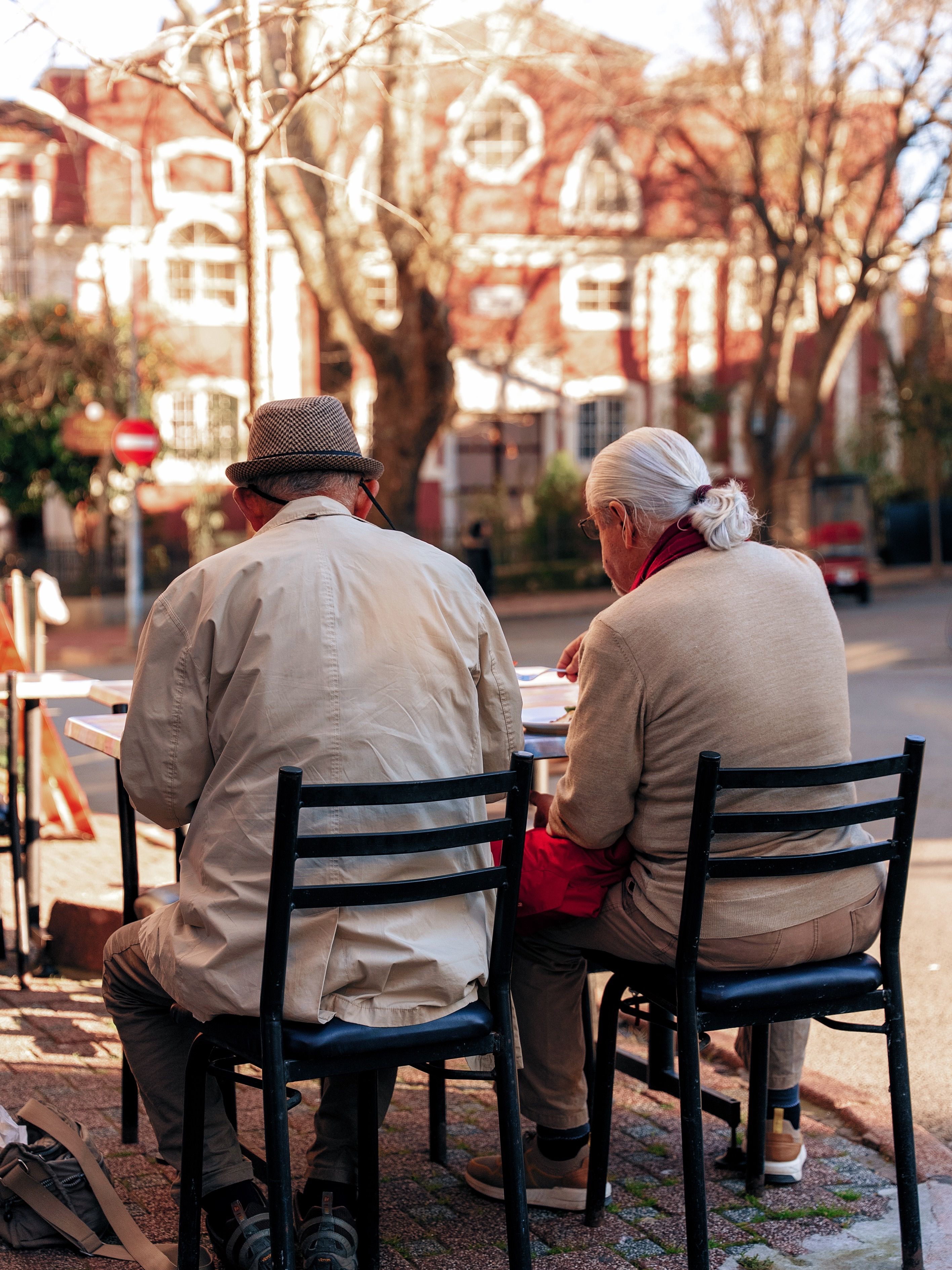 Elderly Couple Enjoying Outdoor Cafe Seating · Free Stock Photo