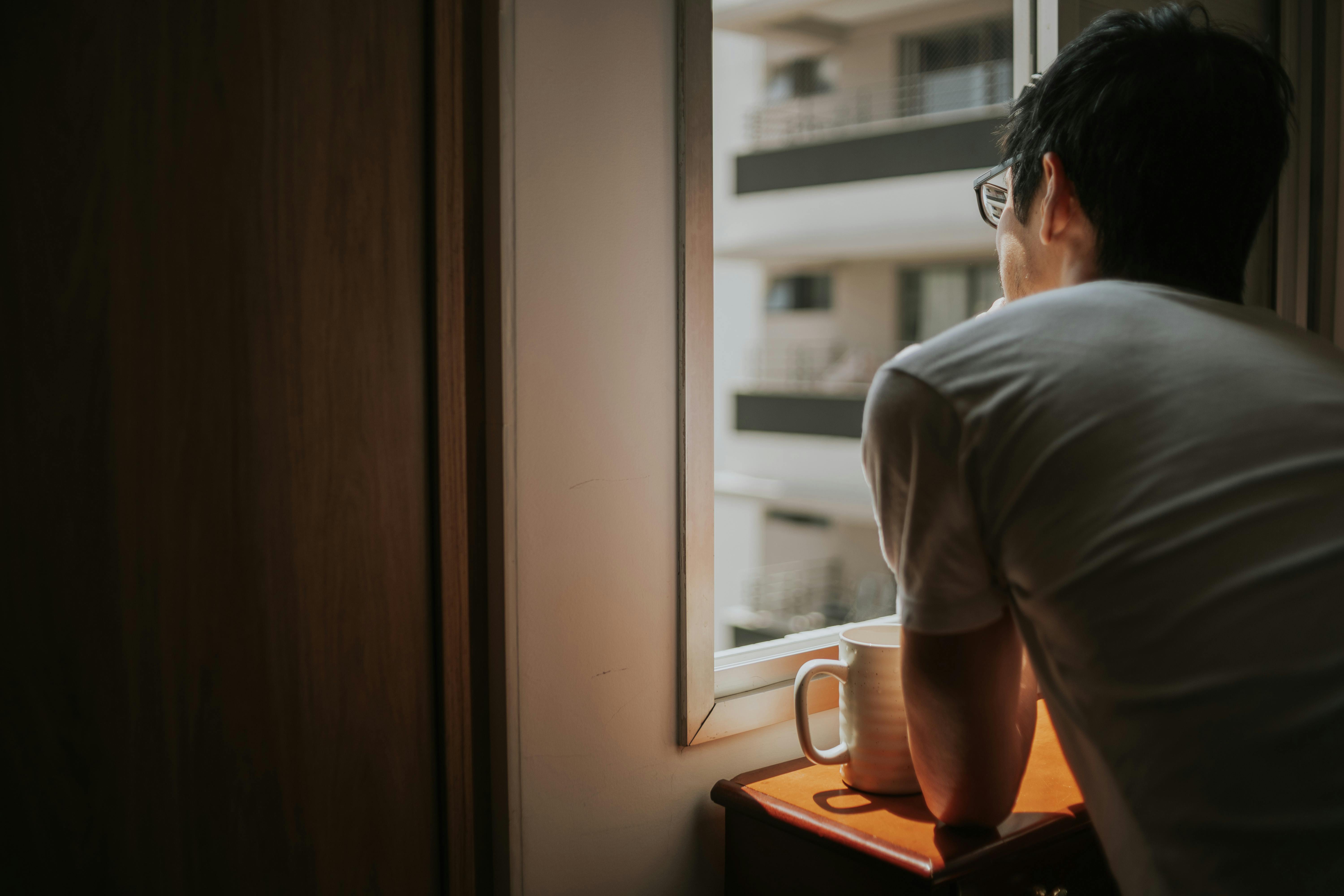 Contemplative Man Gazing Out Urban Window · Free Stock Photo