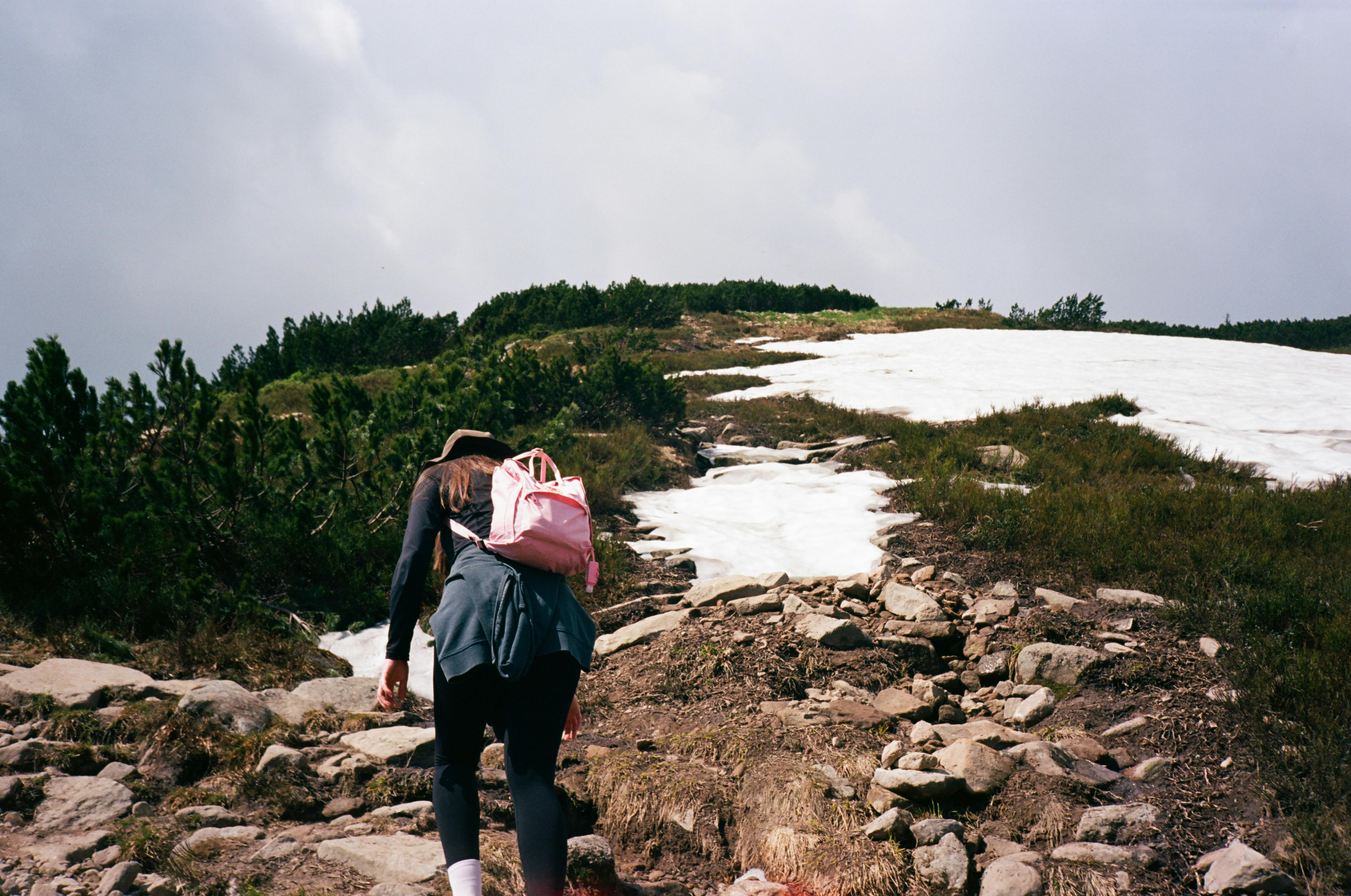 Hiker Ascending Rocky Mountain Path in Spring Snow · Free Stock Photo