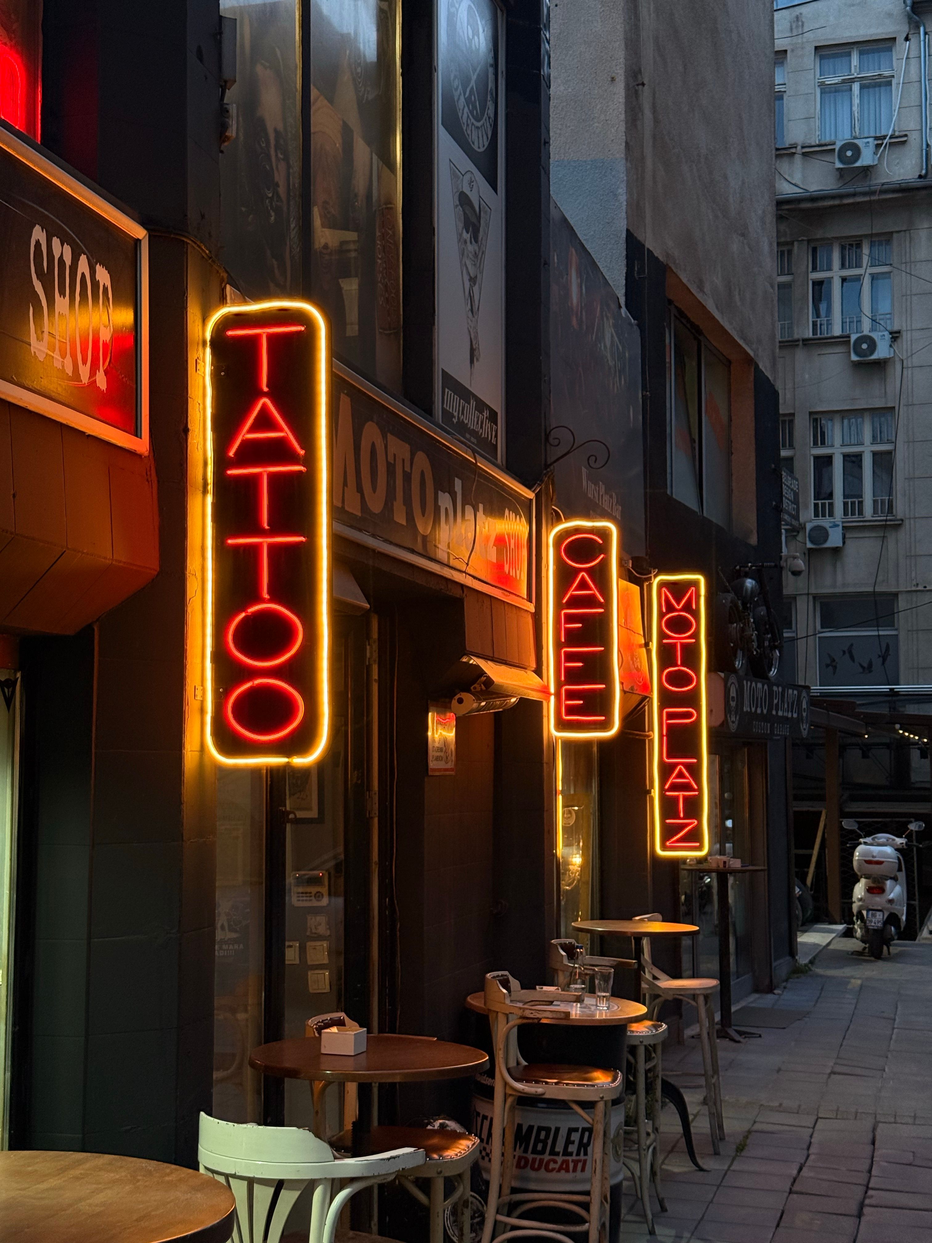 Urban Alley with Neon Tattoo and Caffe Signs · Free Stock Photo