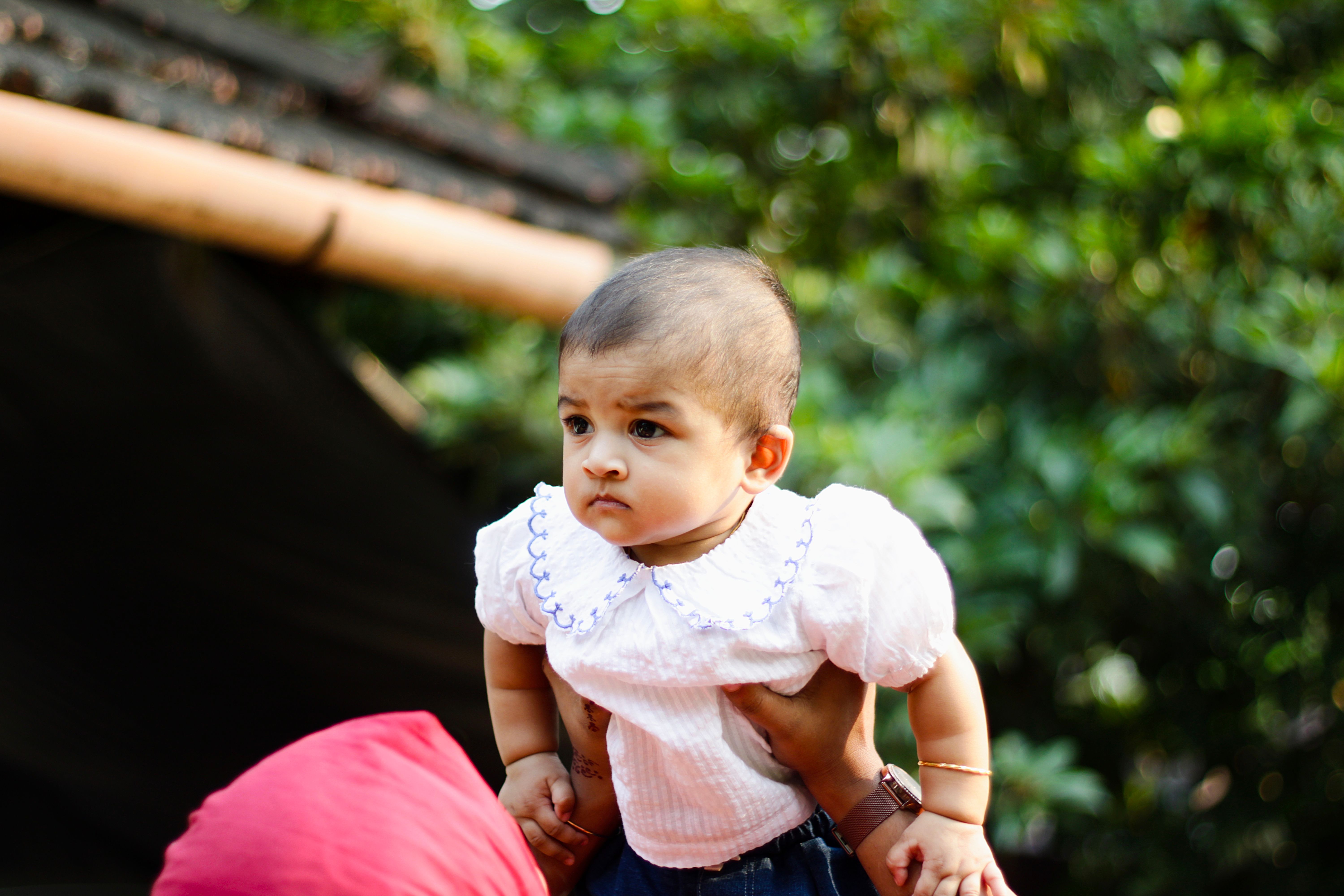Adorable Baby Held Outdoors in Bright Sunlight · Free Stock Photo