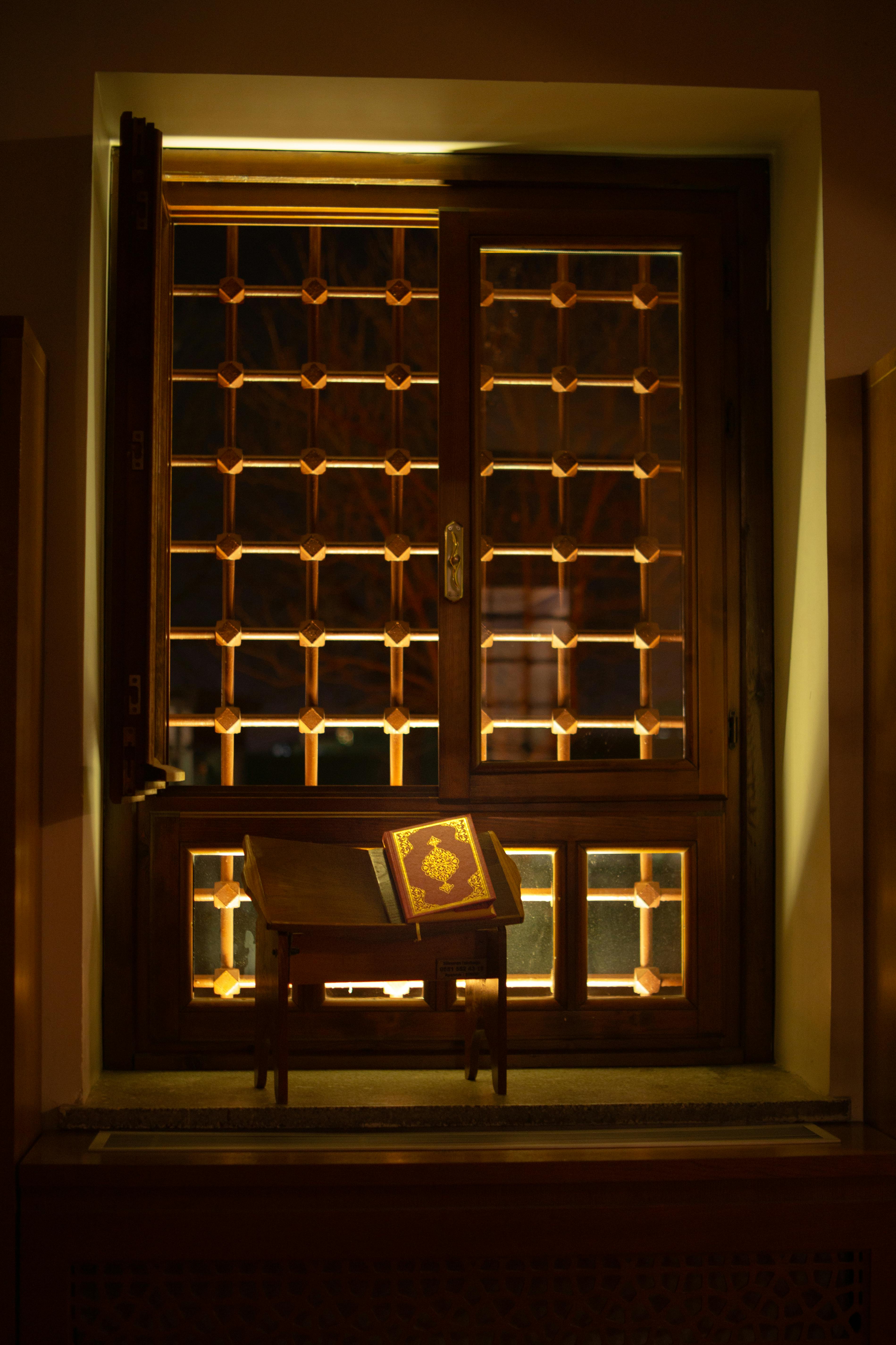 Quran on Wooden Stand by Illuminated Window · Free Stock Photo