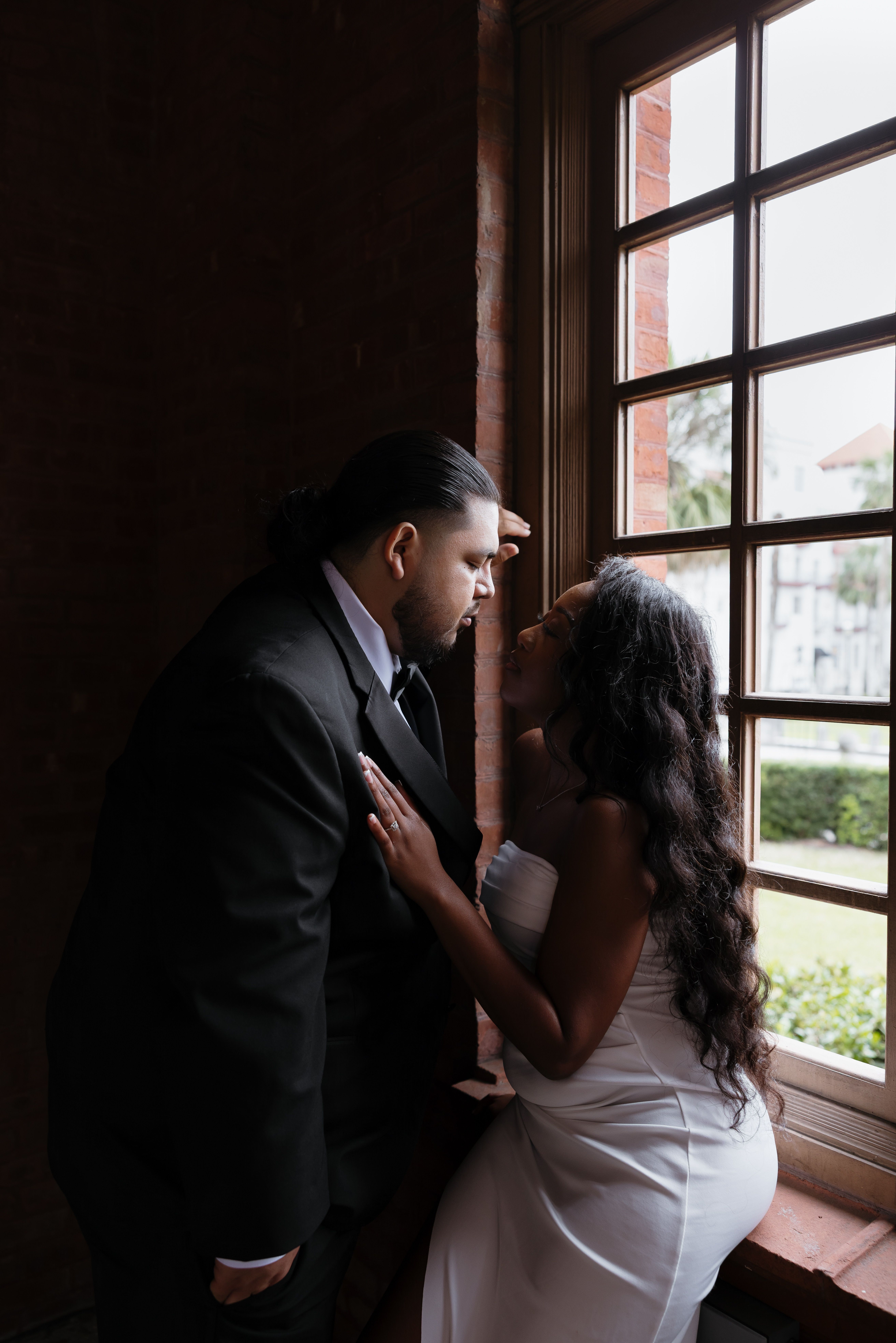 Romantic Couple by a Window in Elegant Attire · Free Stock Photo