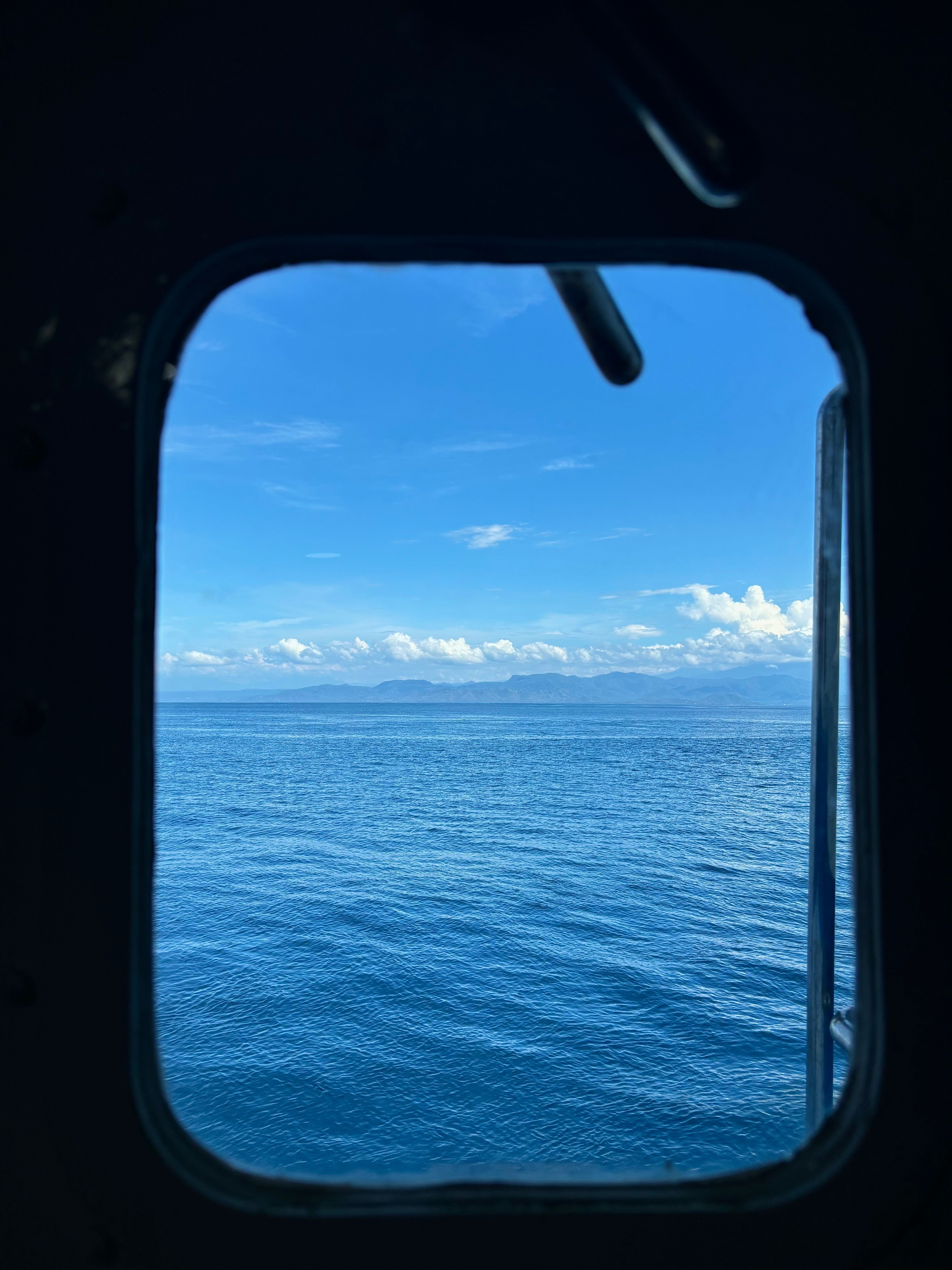 A porthole window looking out at the ocean · Free Stock Photo