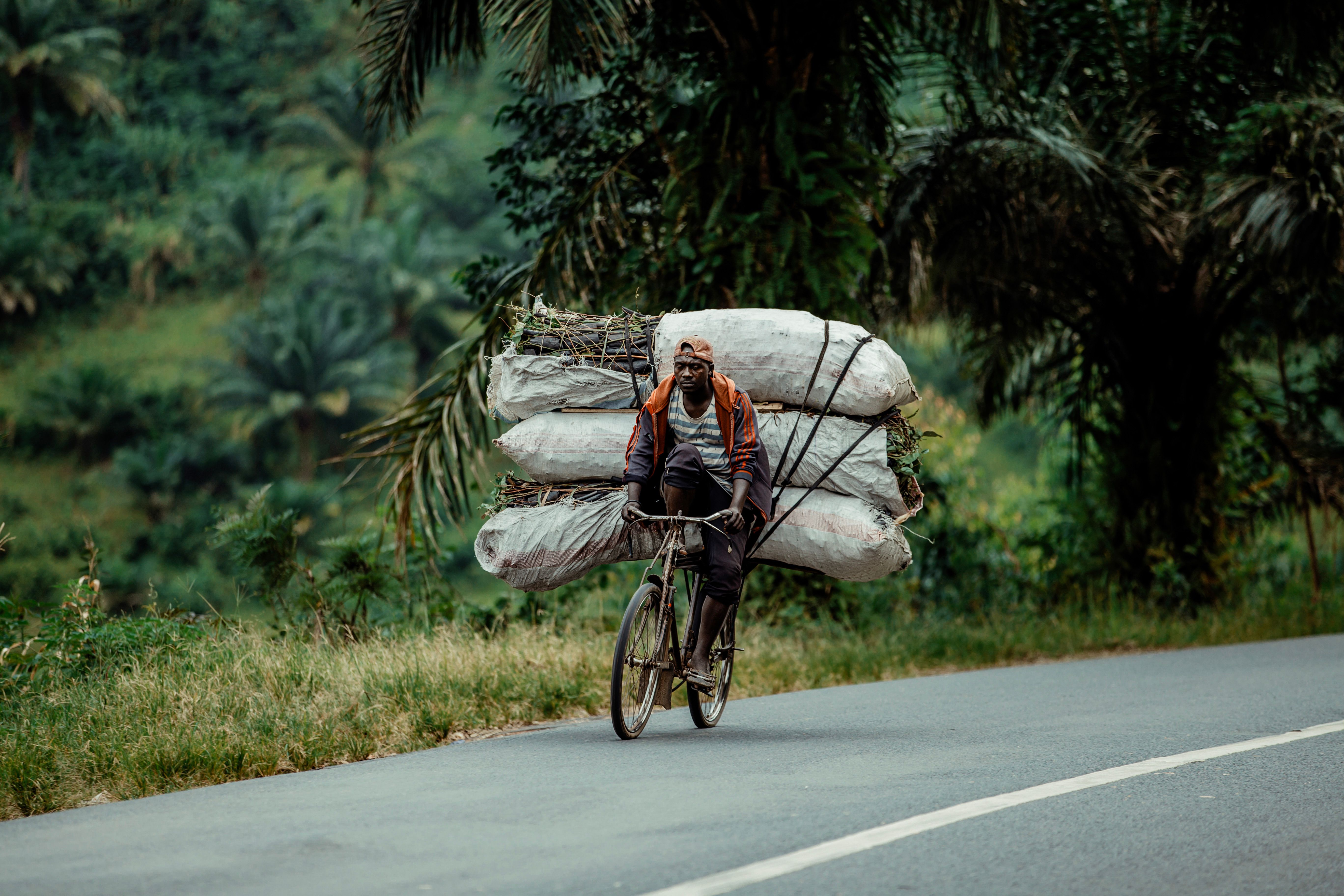 Man Cycling on Road with Heavy Load in Rural Area · Free Stock Photo
