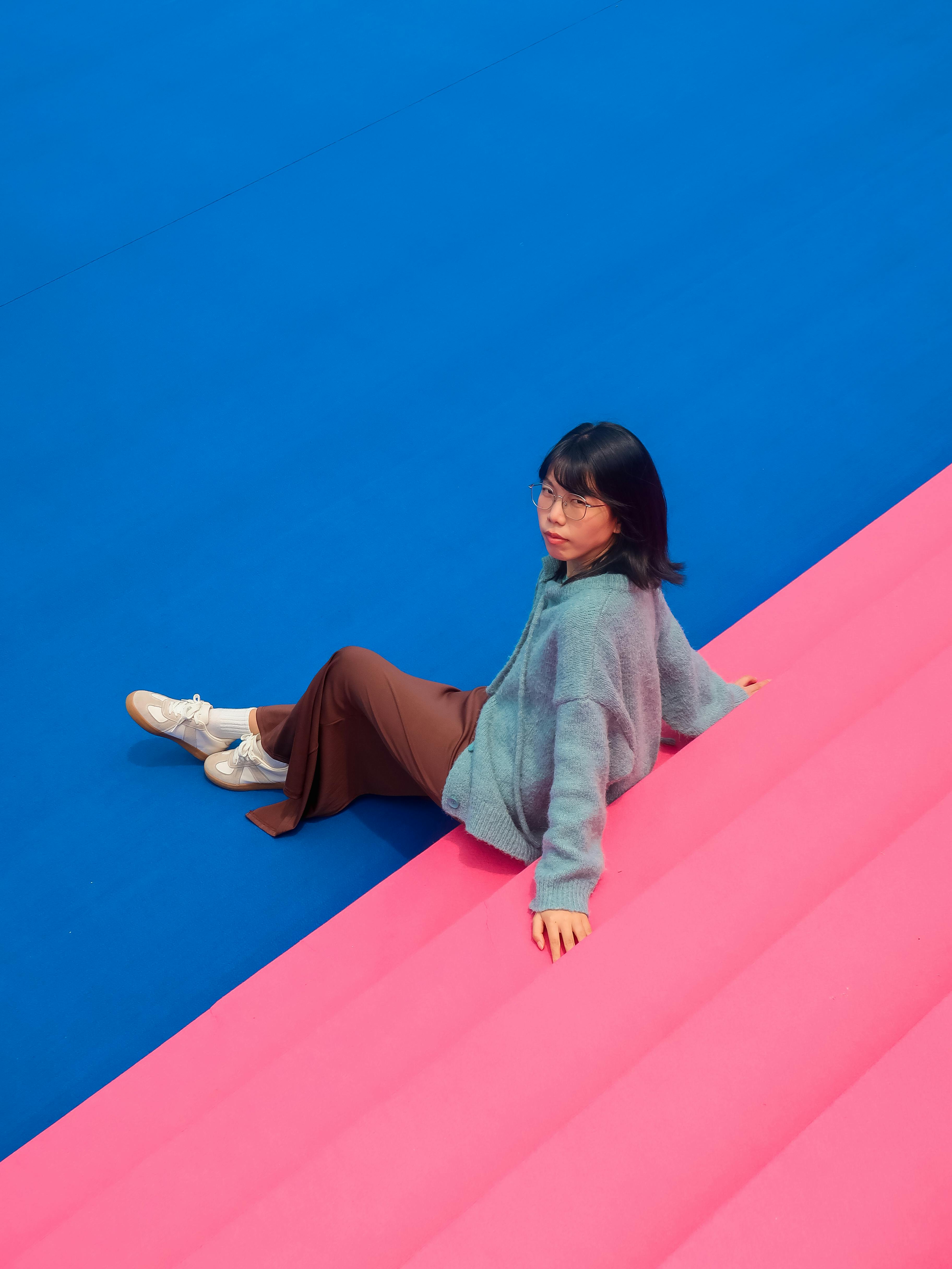 Young Woman Relaxing on Vibrant Pink Steps · Free Stock Photo