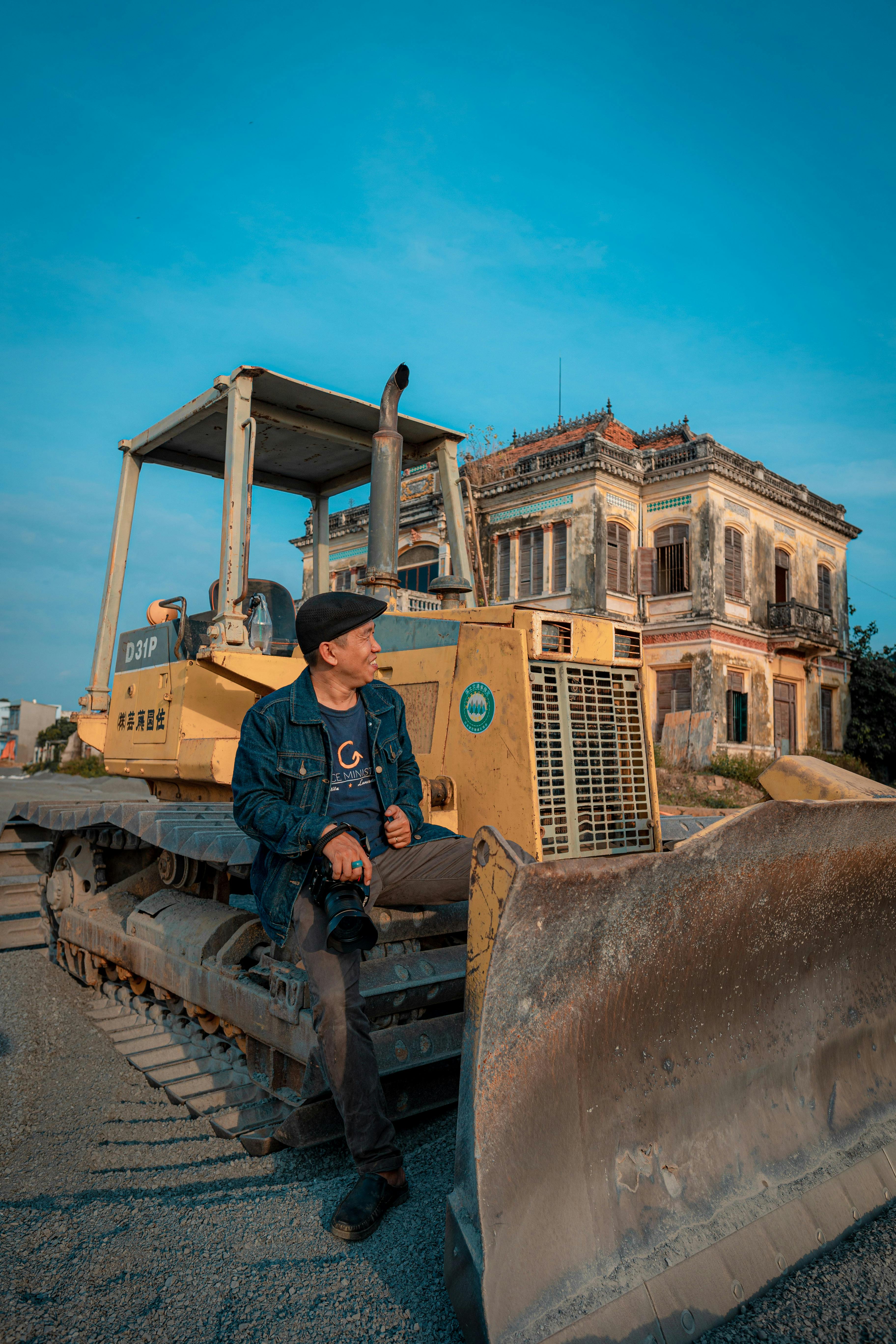 Man Sitting on Bulldozer in Front of Old Building · Free Stock Photo
