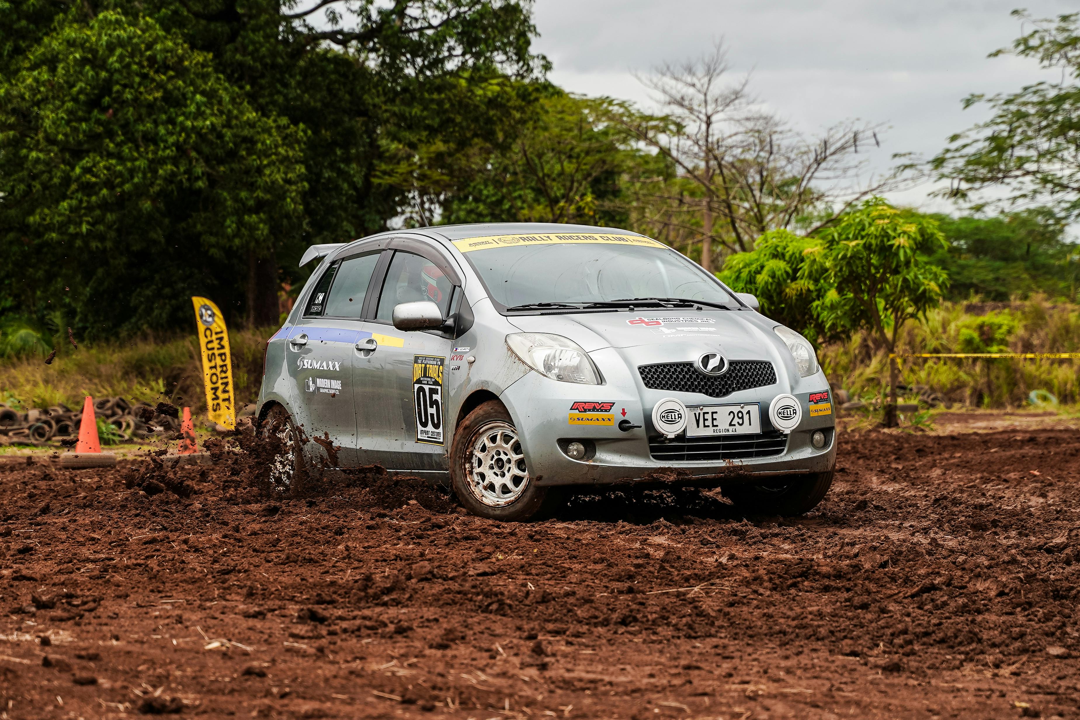 Silver rally car speeding through muddy track outdoors · Free Stock Photo