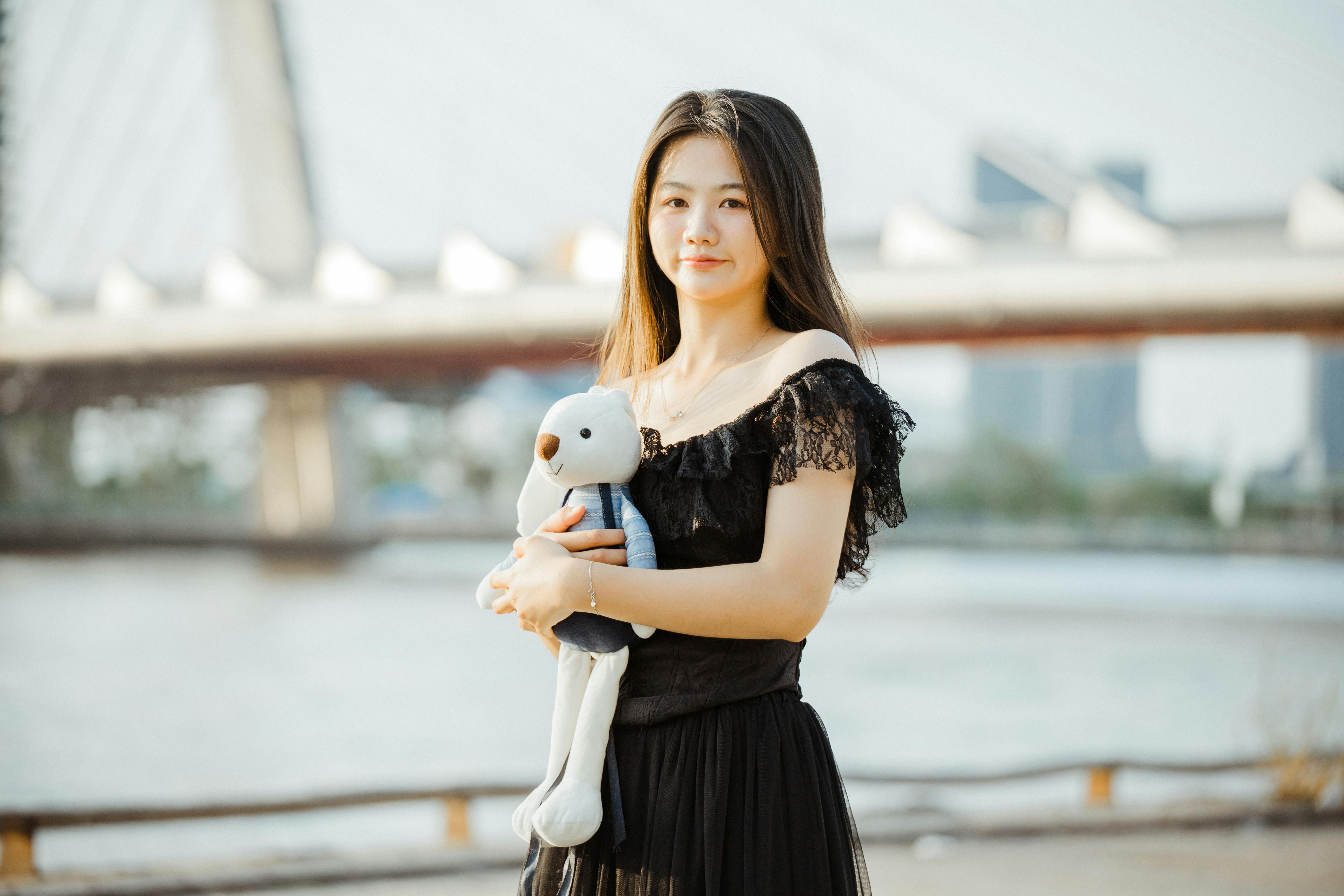 Young Woman Holding Teddy Bear Near Bridge · Free Stock Photo