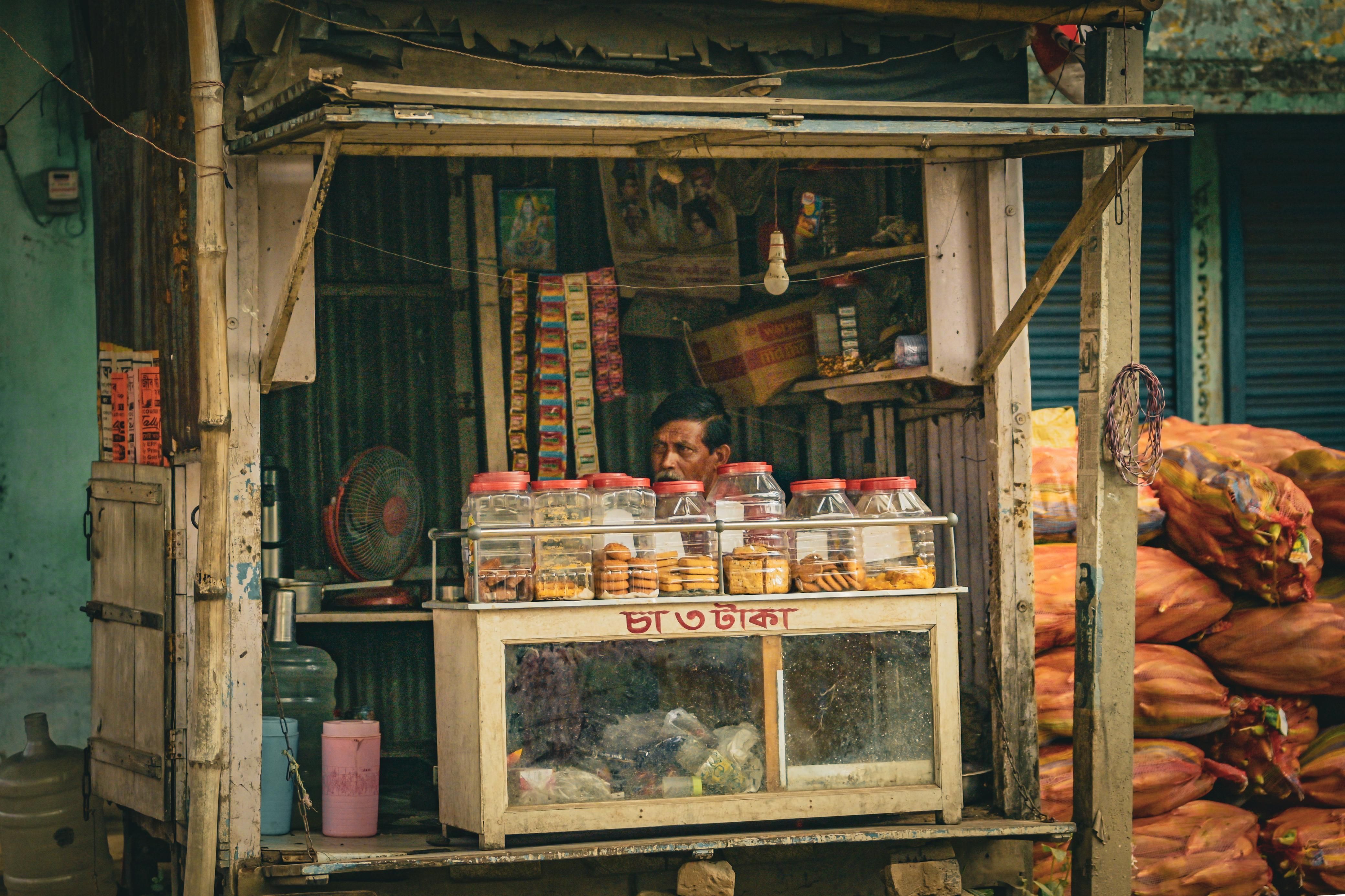 Street Vendor Selling Snacks in Rustic Stall · Free Stock Photo
