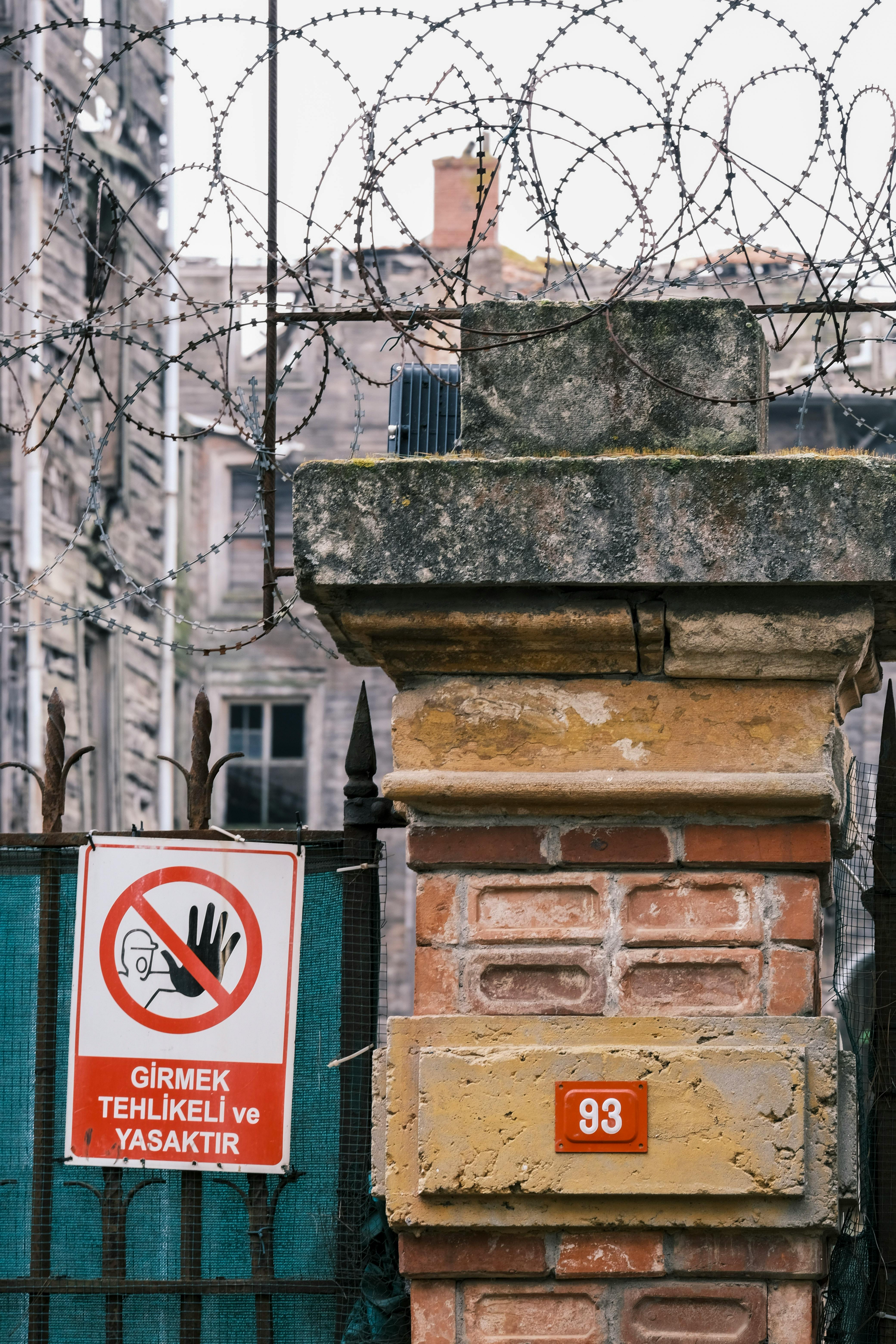 Barbed Wire Wall with Warning Sign in Urban Setting · Free Stock Photo