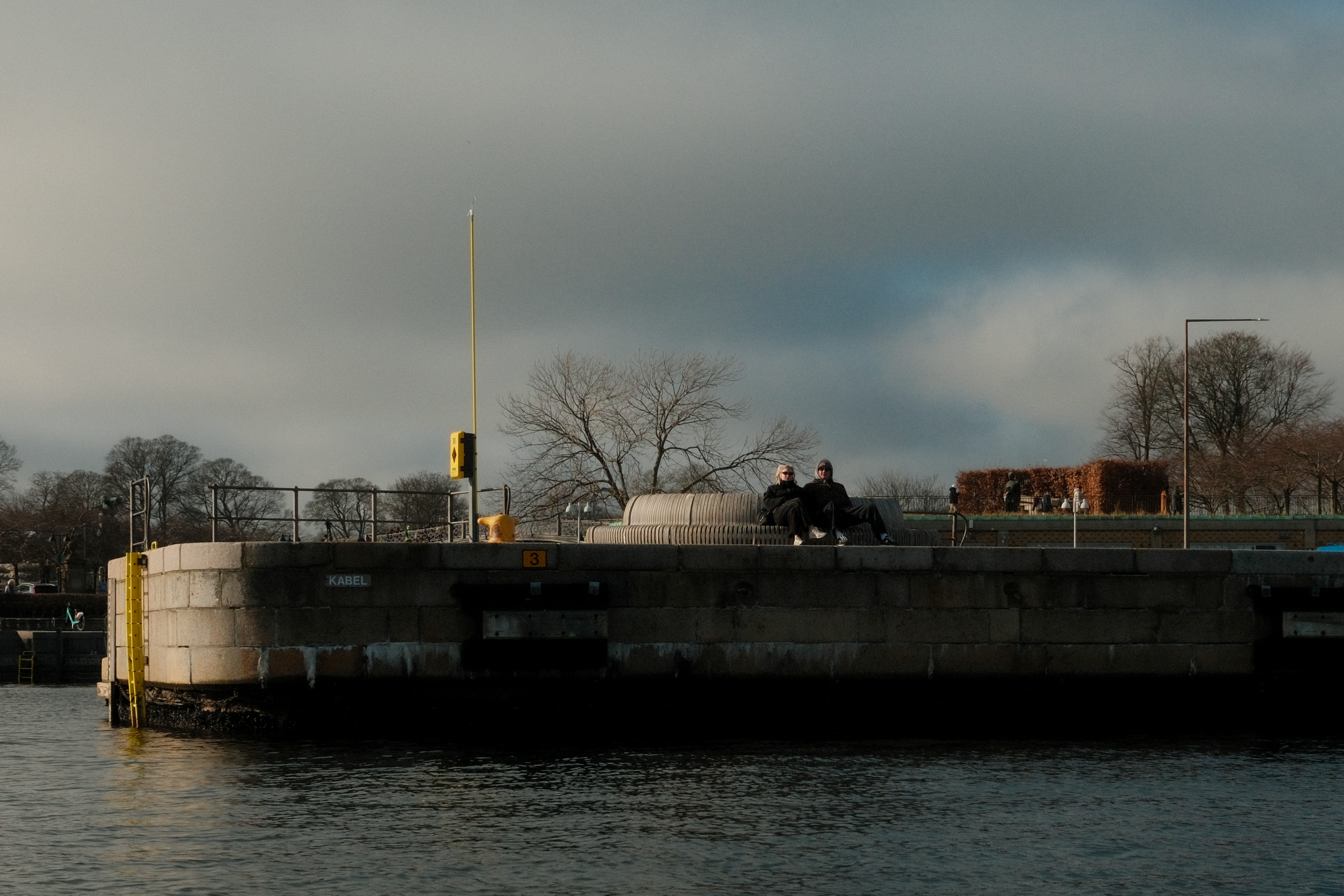 Two People Relaxing on a Waterfront Pier · Free Stock Photo