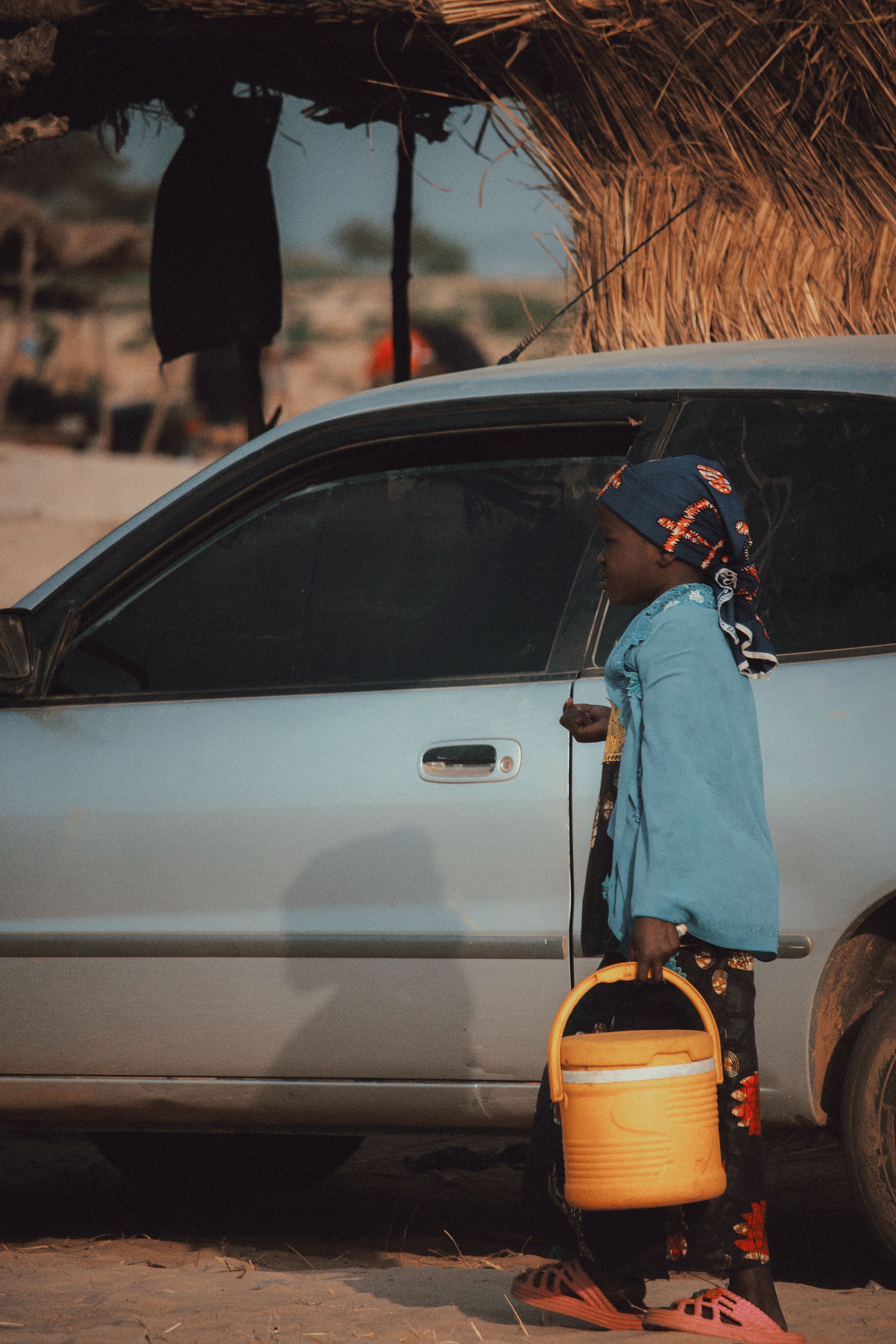 Young Girl with Watering Can by Car Outdoors · Free Stock Photo