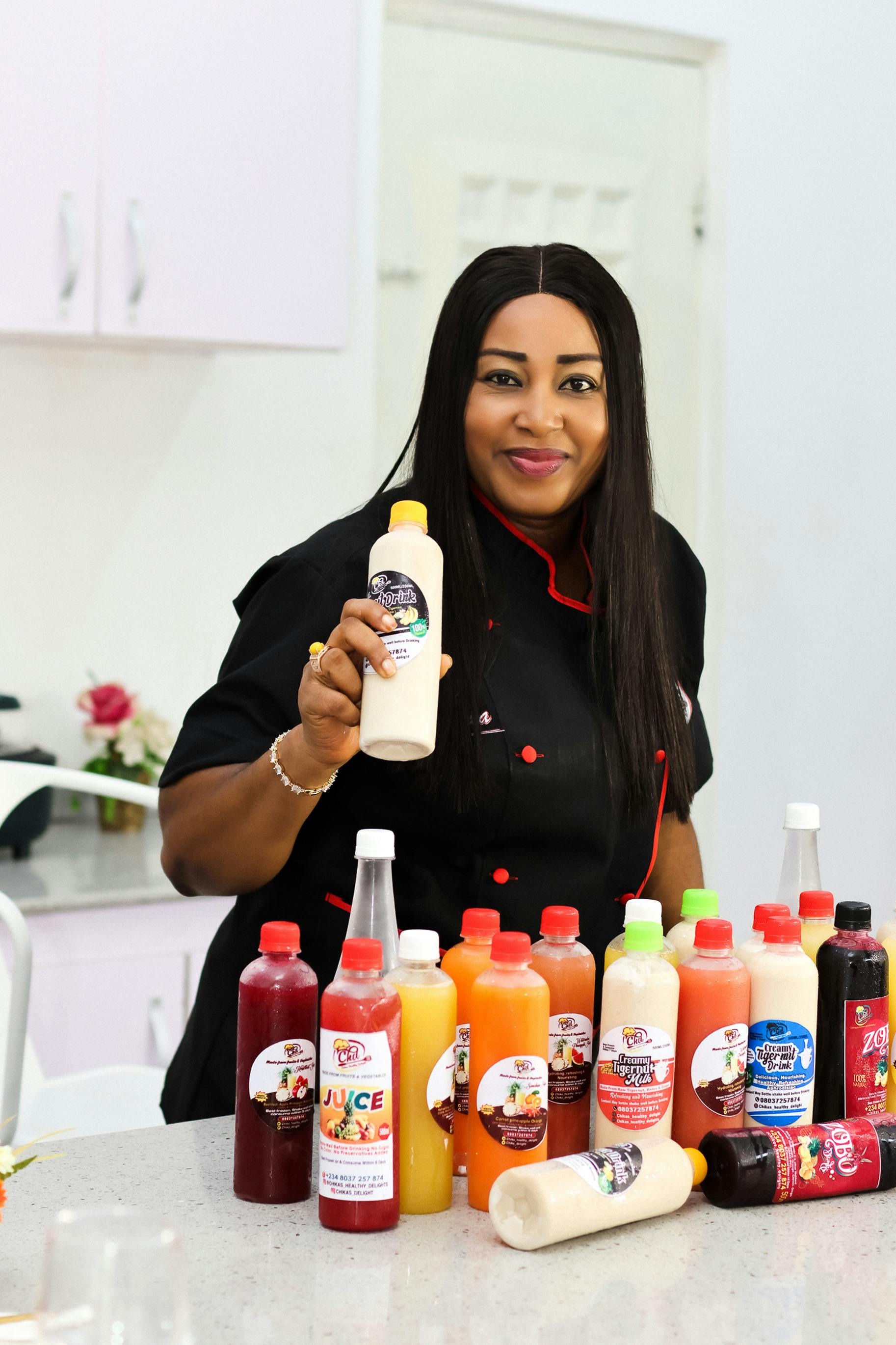Female Chef Displaying Assorted Bottled Juices · Free Stock Photo