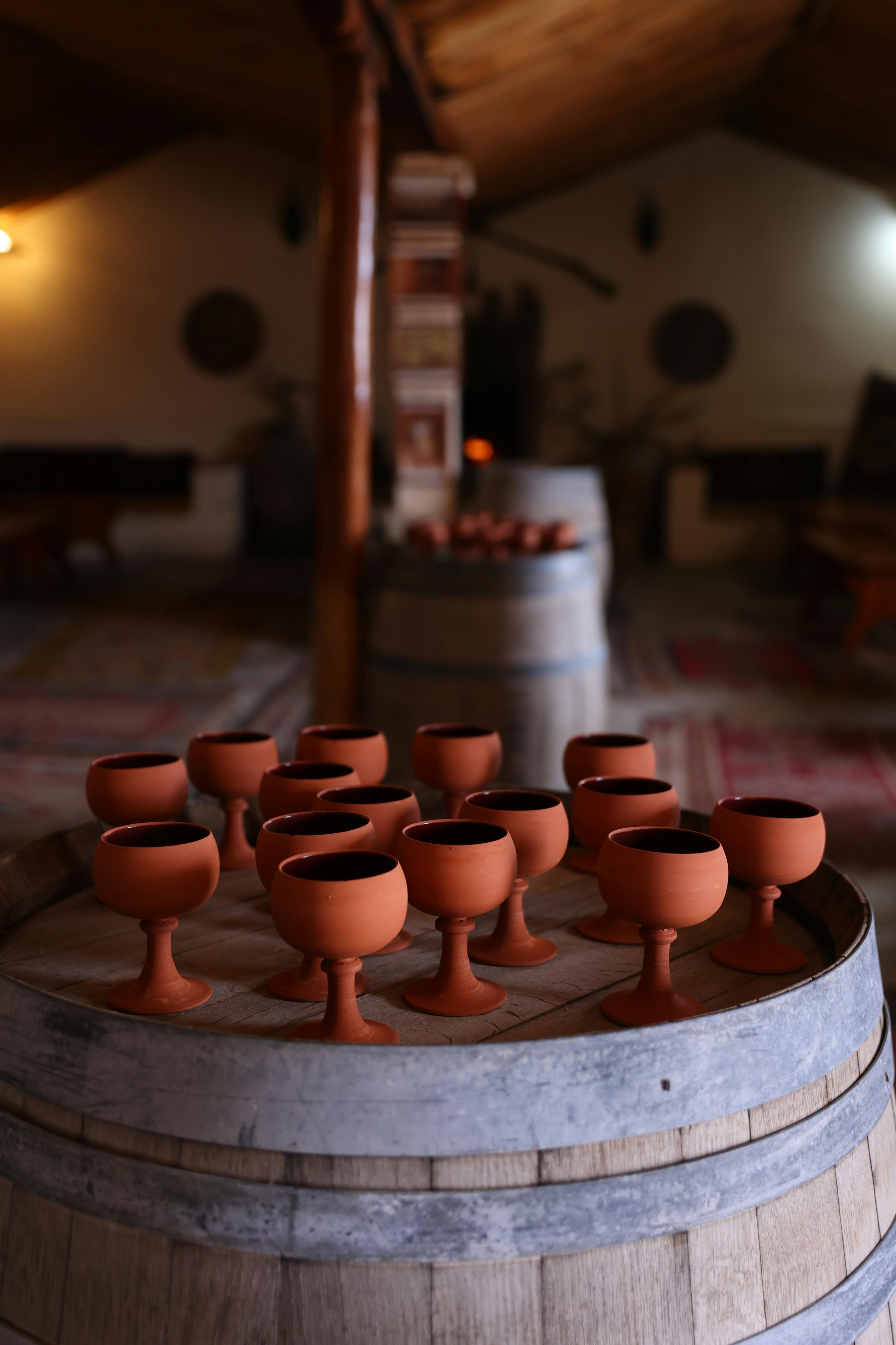 Rustic Clay Goblets on Wooden Barrel Indoors · Free Stock Photo